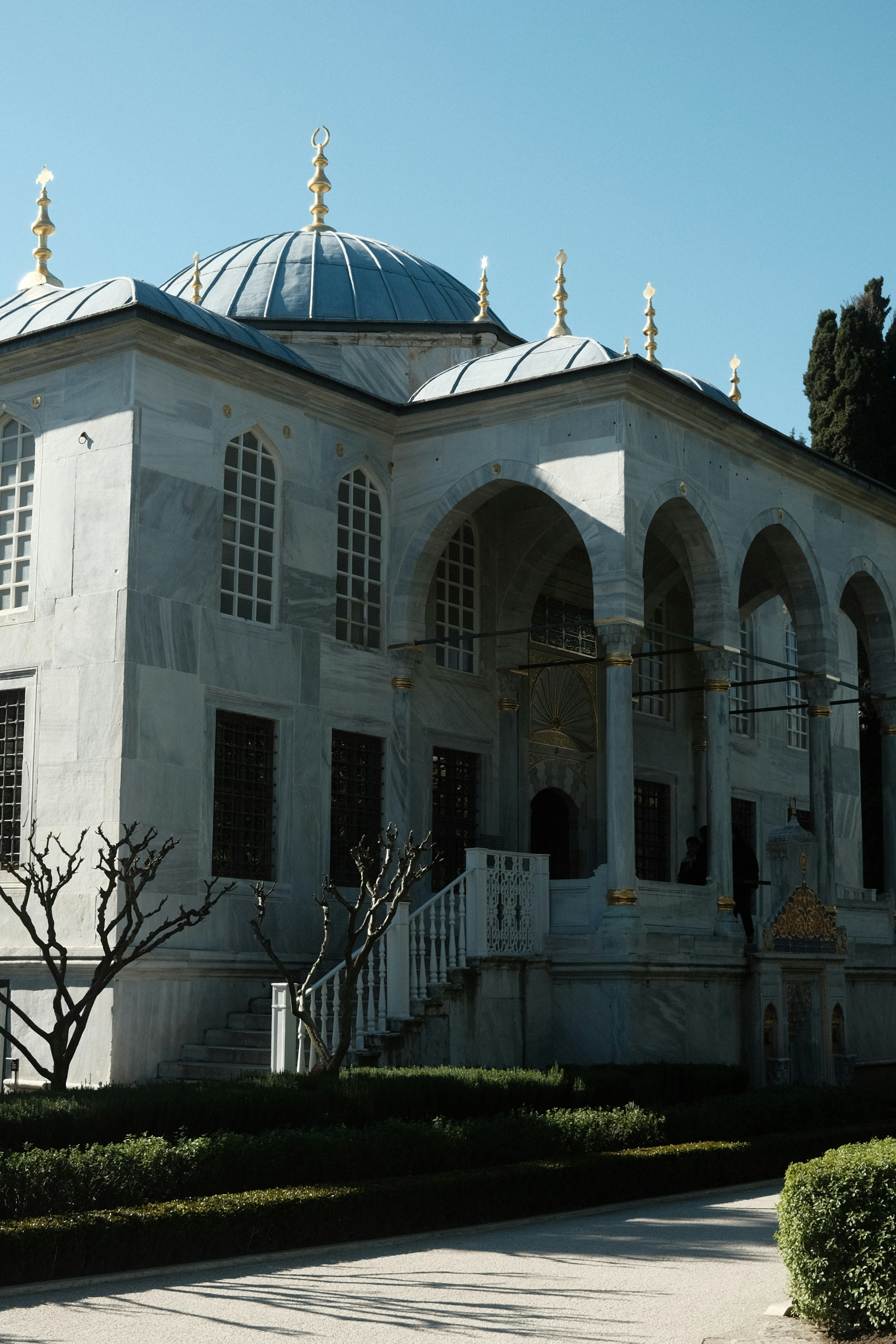 Blue Domes Over Marble Facade: Sunlit Arches in Clear Sky