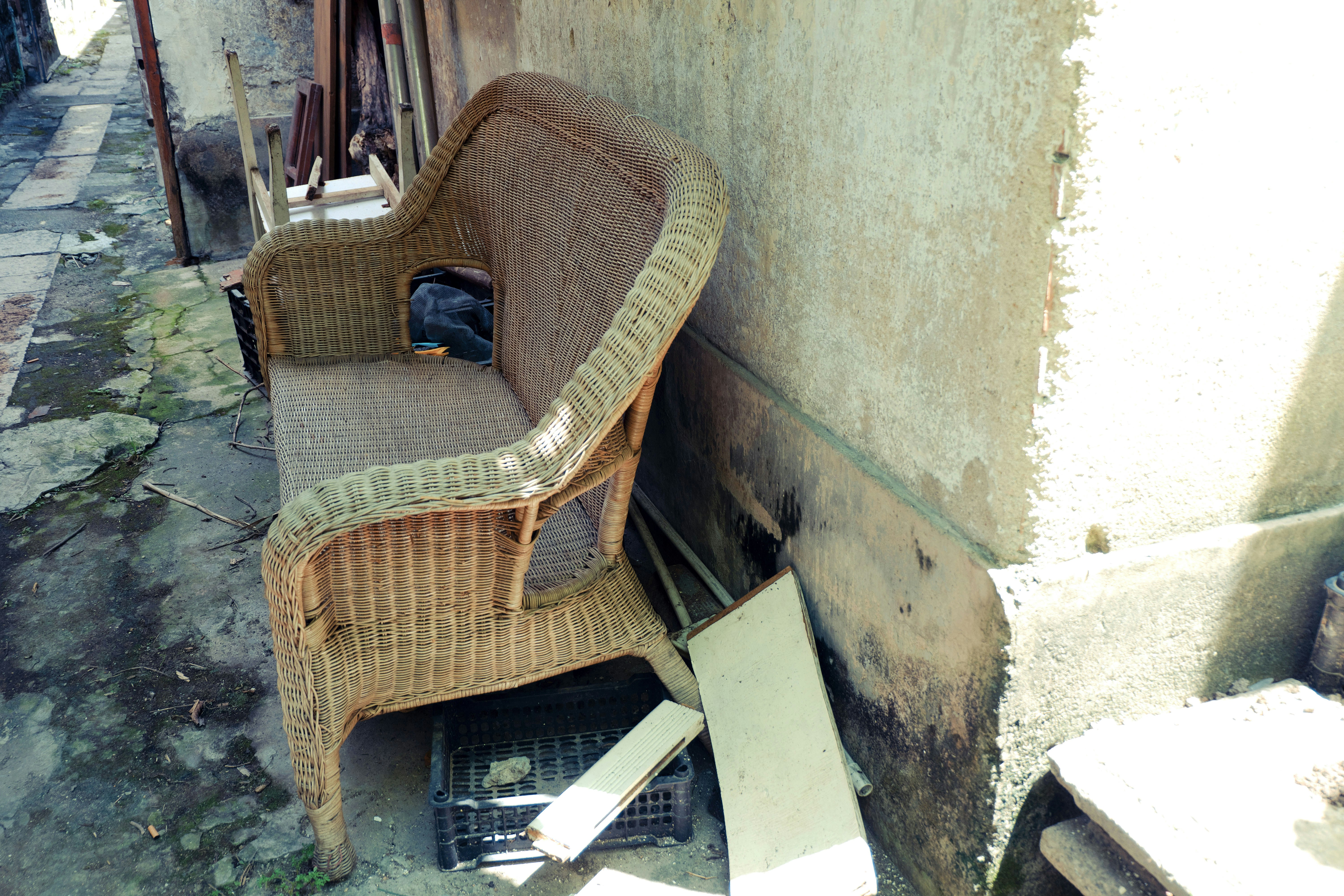 Sunlit Relic: Wicker Chair in a Weathered Alley