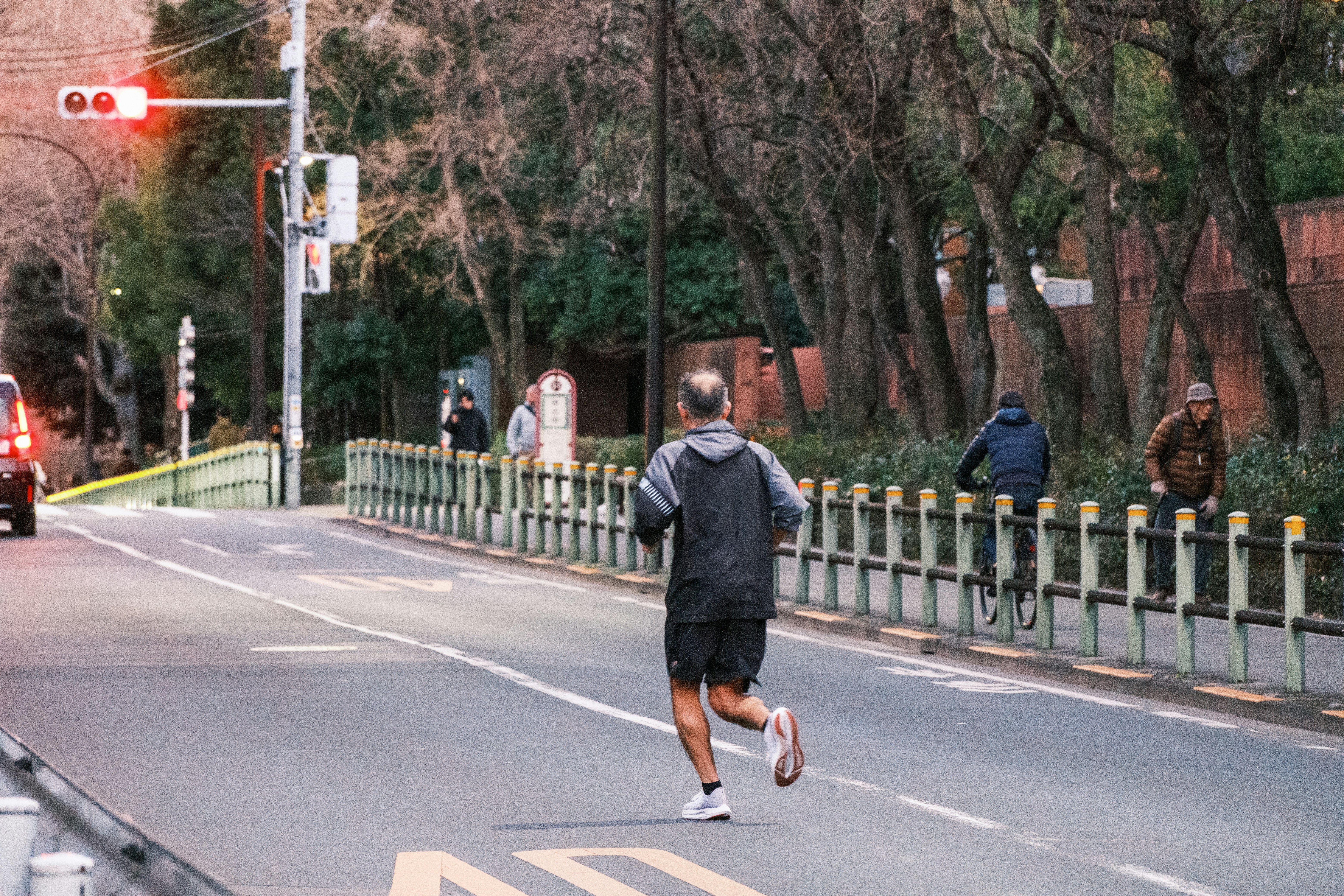 A man running across a street next to a traffic light photo – Free ...
