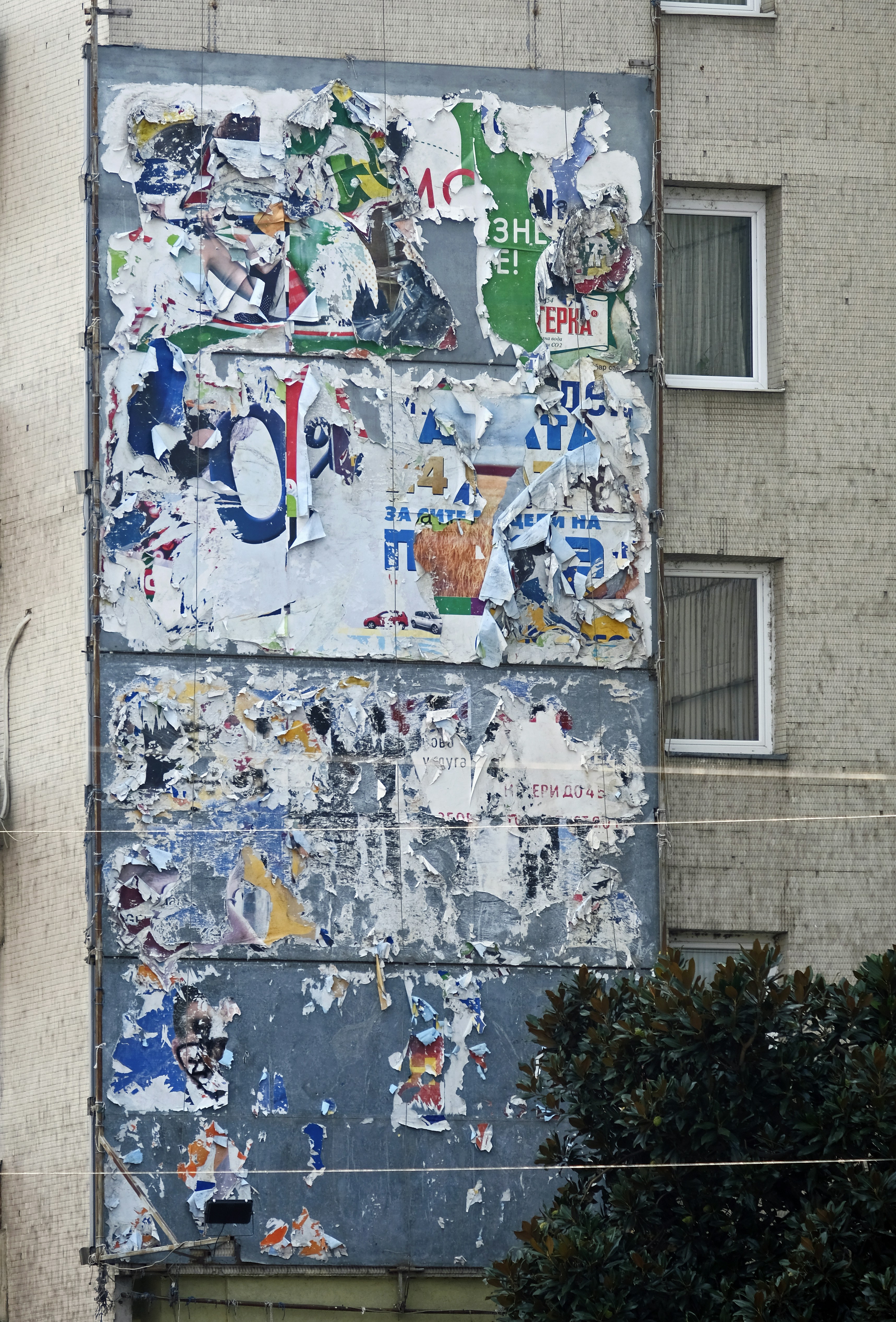 Ad board with multiple layers of old advertisement posters being pulled down