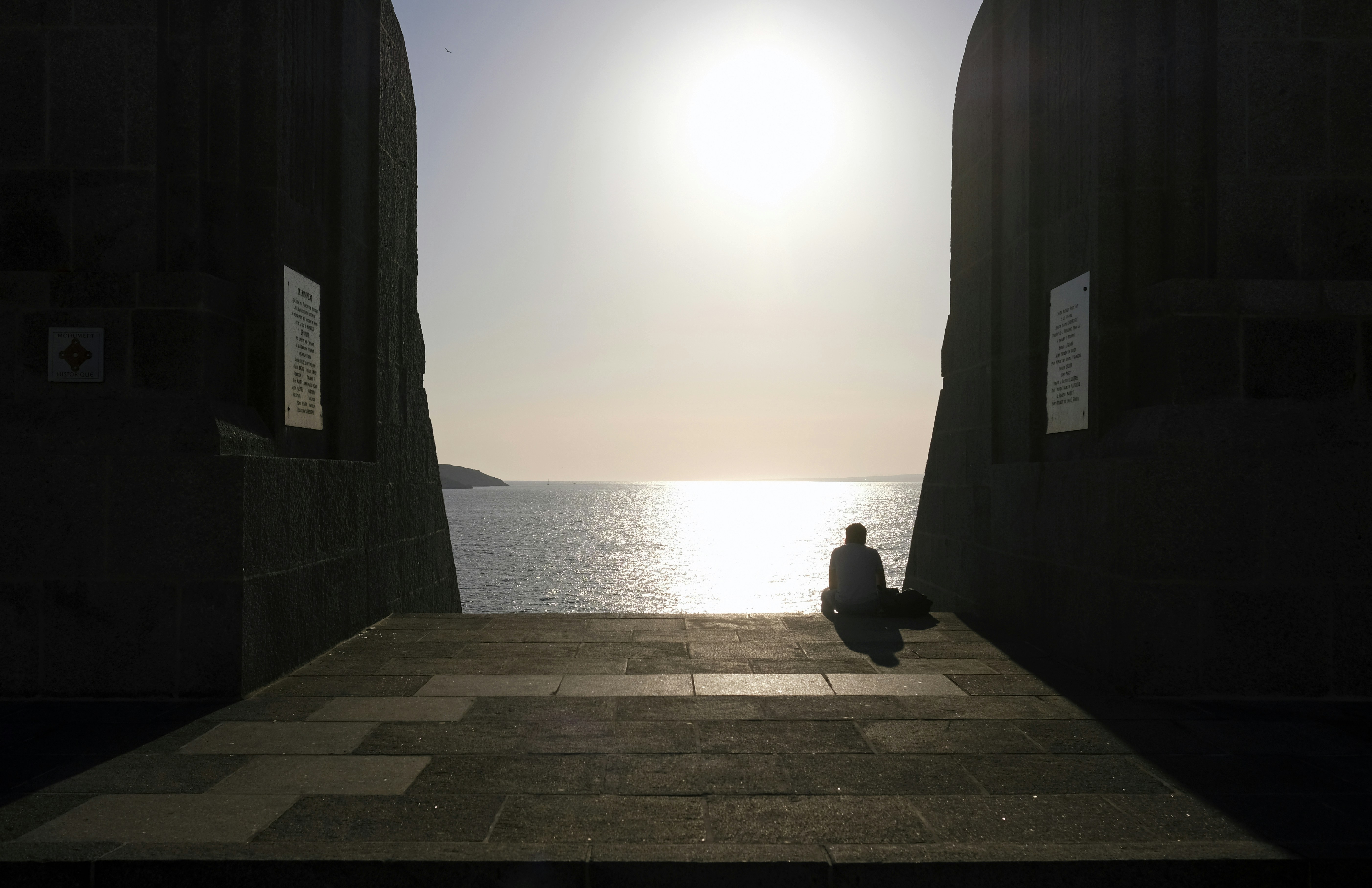 Sunlit Threshold: A Solitary Silhouette Between Stone Walls