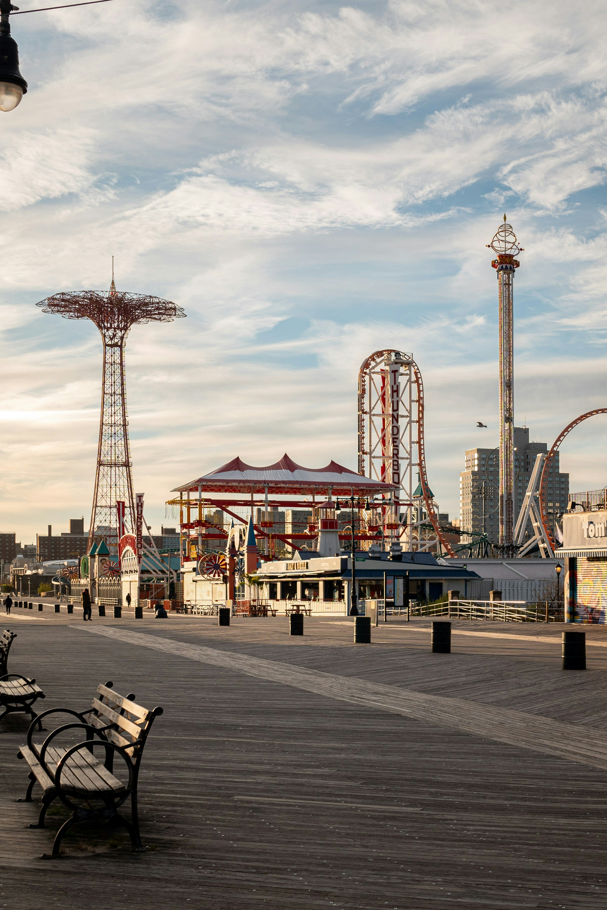 A boardwalk with benches and roller coasters in the background photo ...