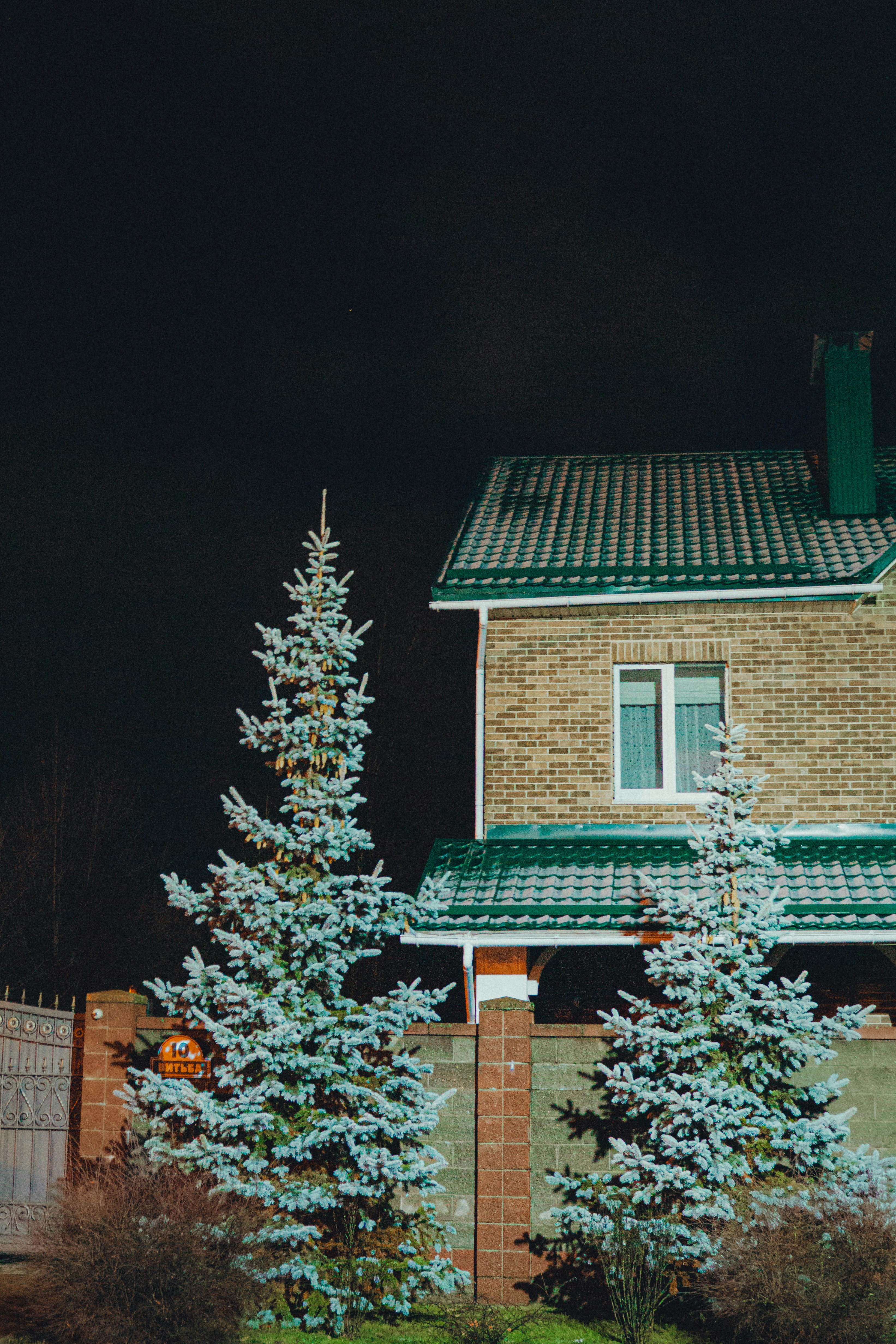 Nightfall on a Snow-Kissed Brick House with a Green Roof