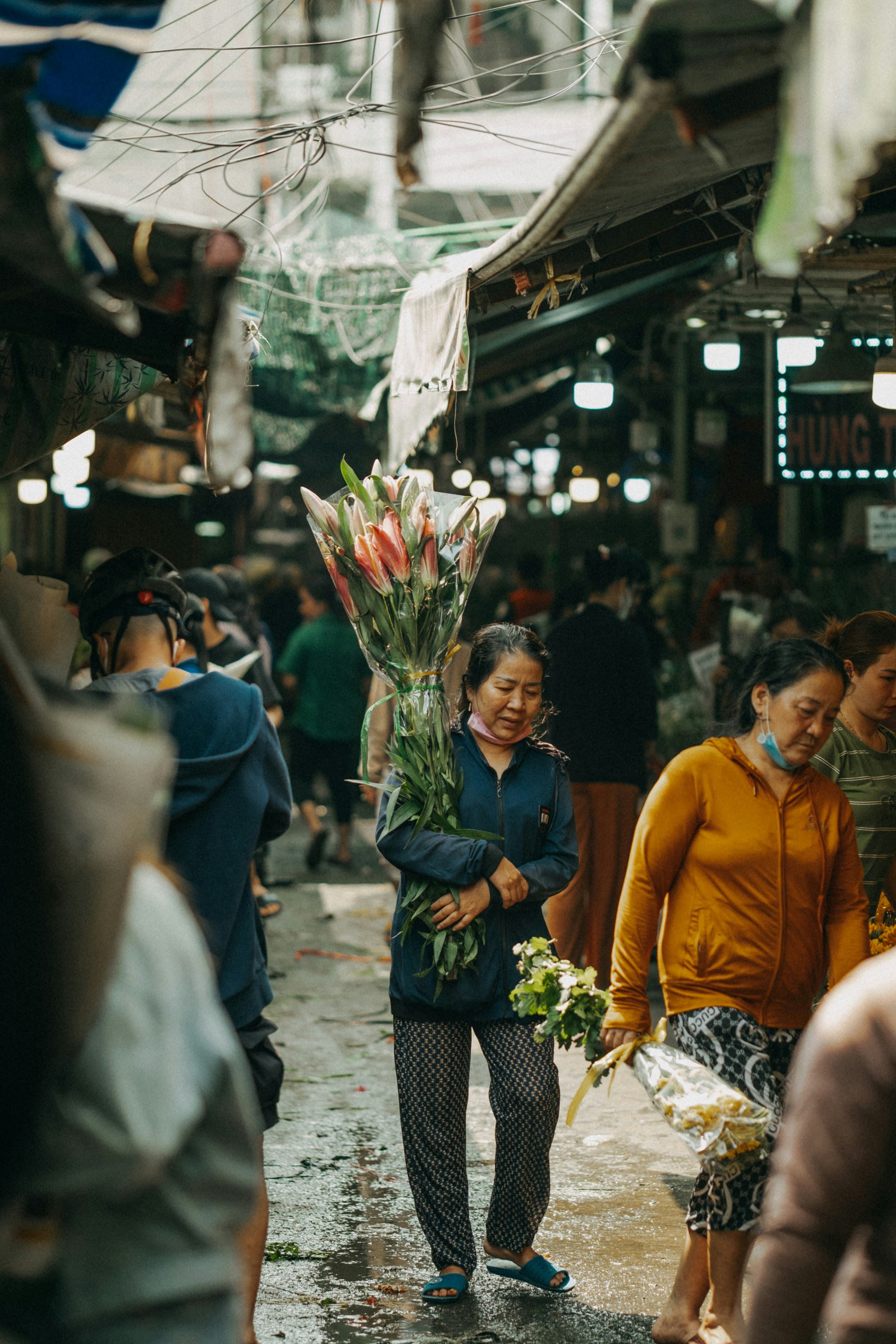 A woman walking down a street holding a bunch of flowers photo – Free ...