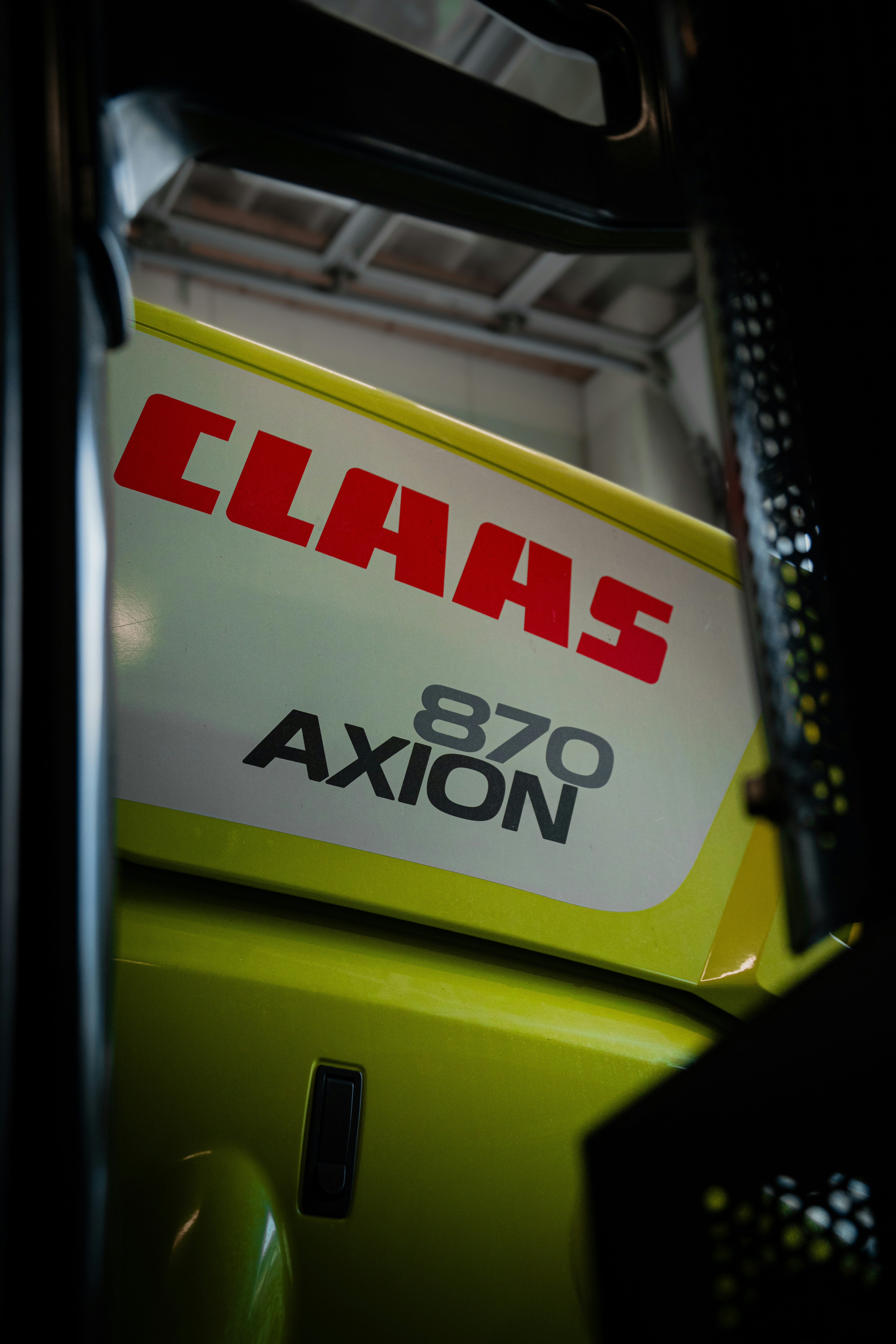 Close‑up of a CLAAS Axion tractor silhouette under workshop lighting