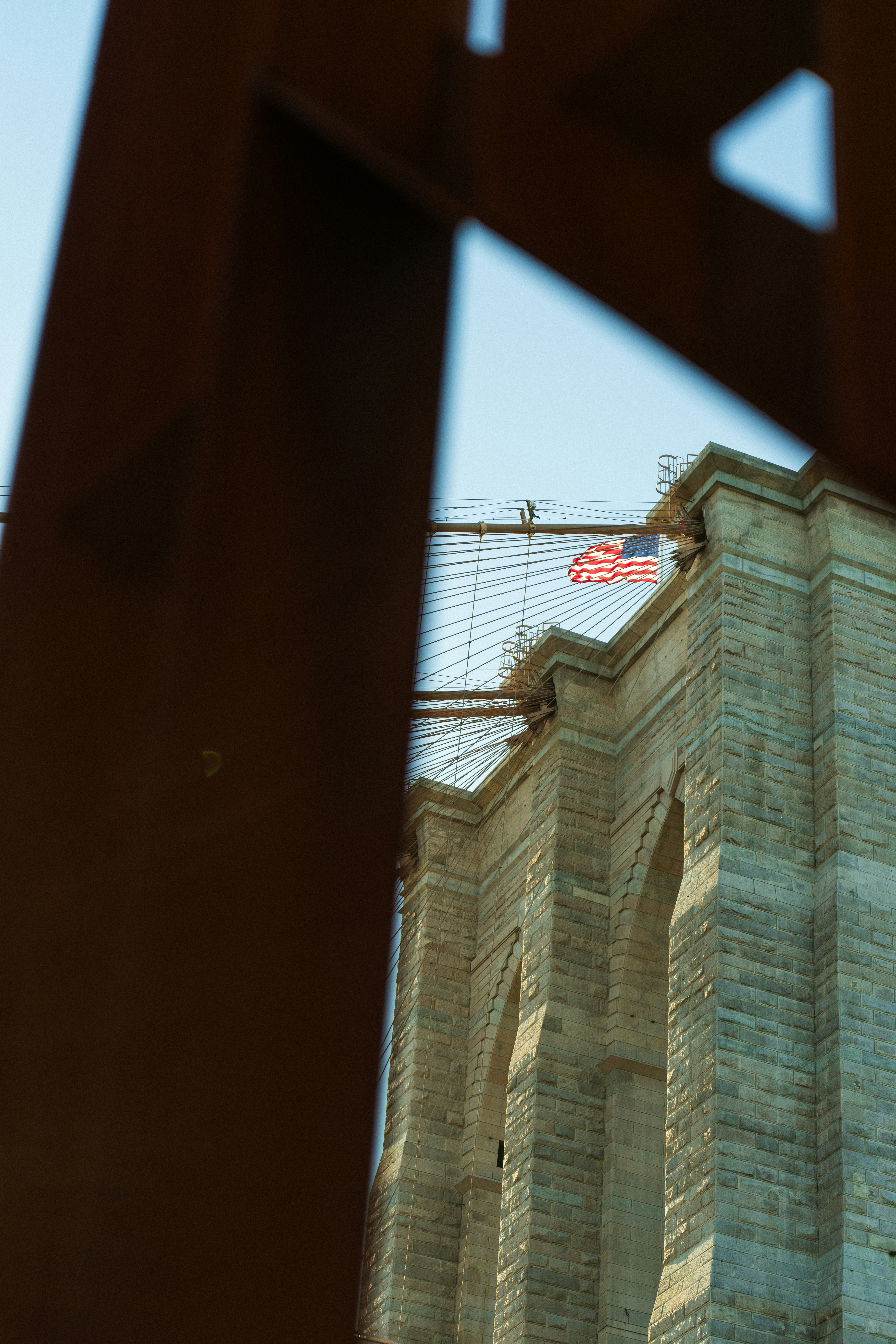 Flag Framed by Steel Beams Over a Stone Bridge Tower