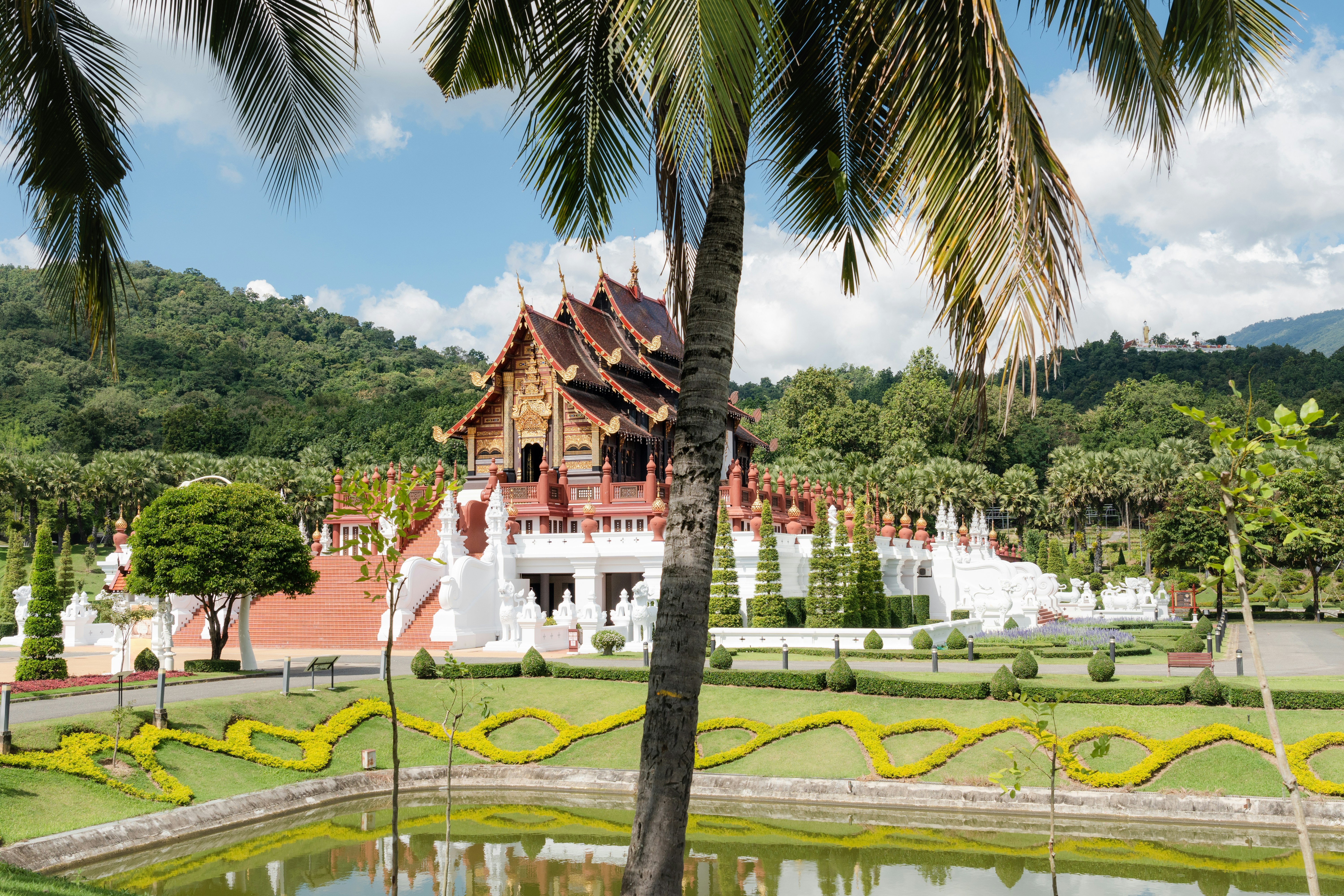 Palm-Framed Thai-Style Temple Surrounded by Symmetrical Gardens and a Reflective Pool