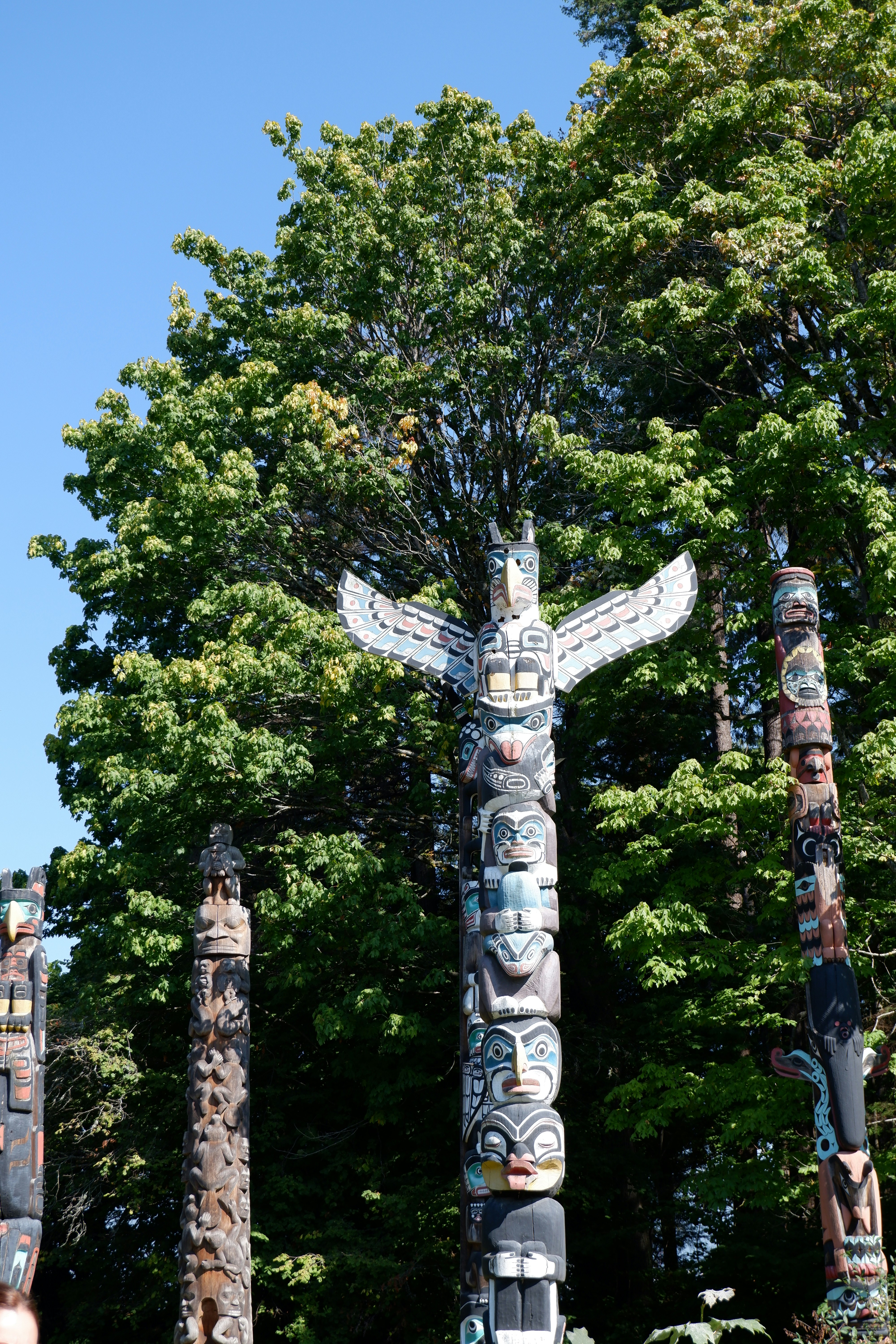 A group of totem poles in front of a tree photo – Free Stanley park ...