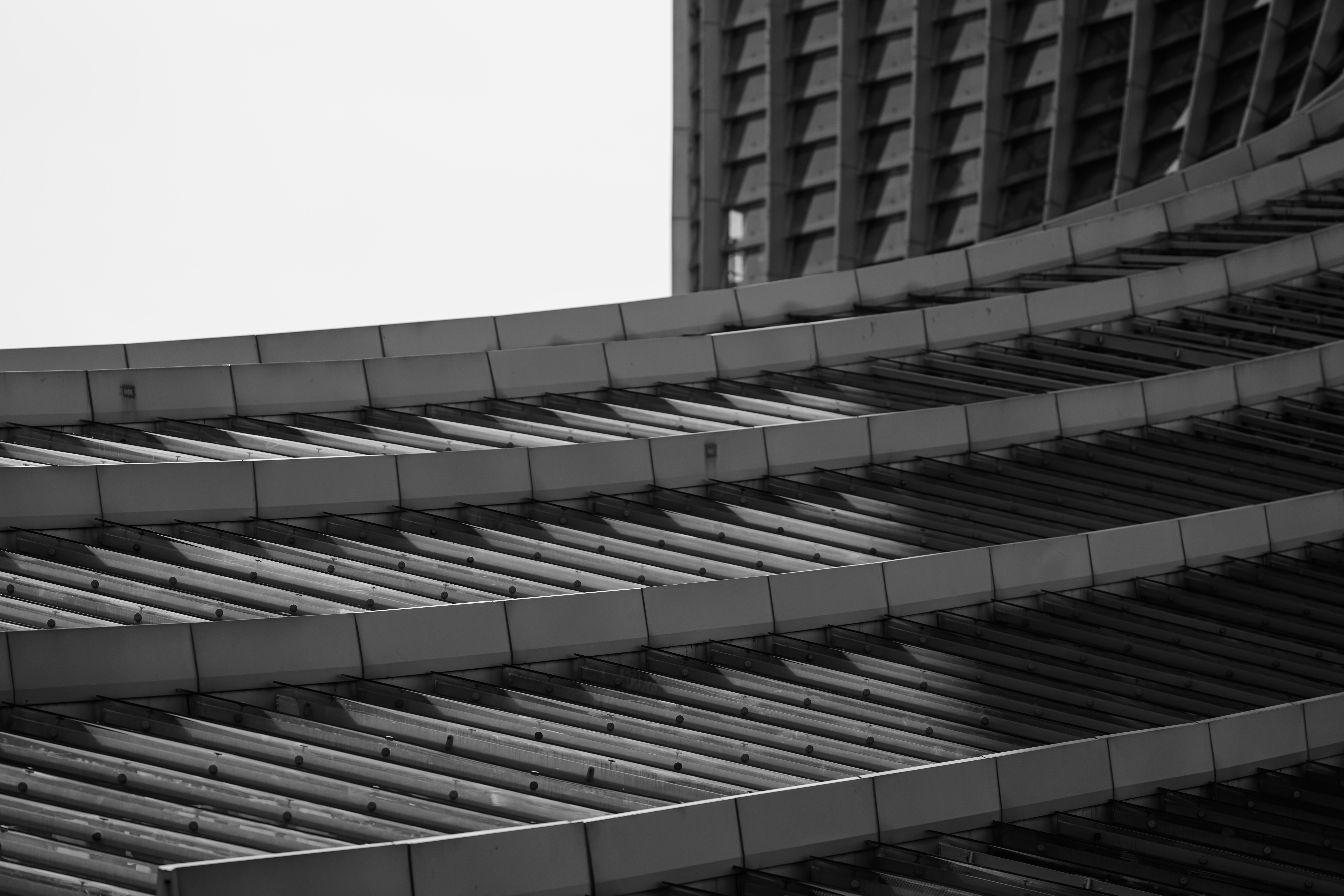 Abstract architectural design showcasing the rhythmic curves and patterns of a building's structure. The monochrome palette emphasizes the interplay of light and shadow.