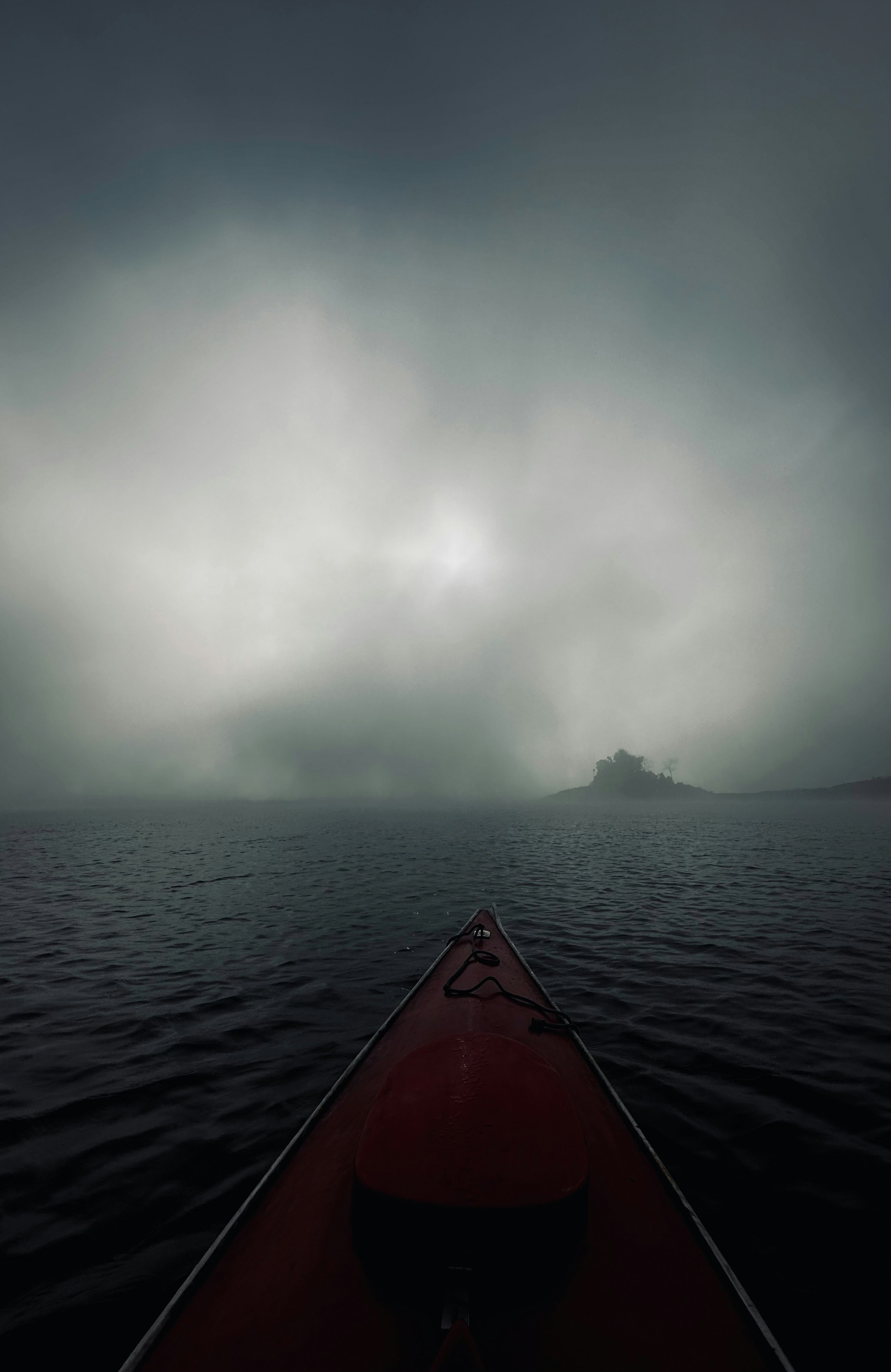 Red Kayak Carving Through Fog Toward a Distant Island