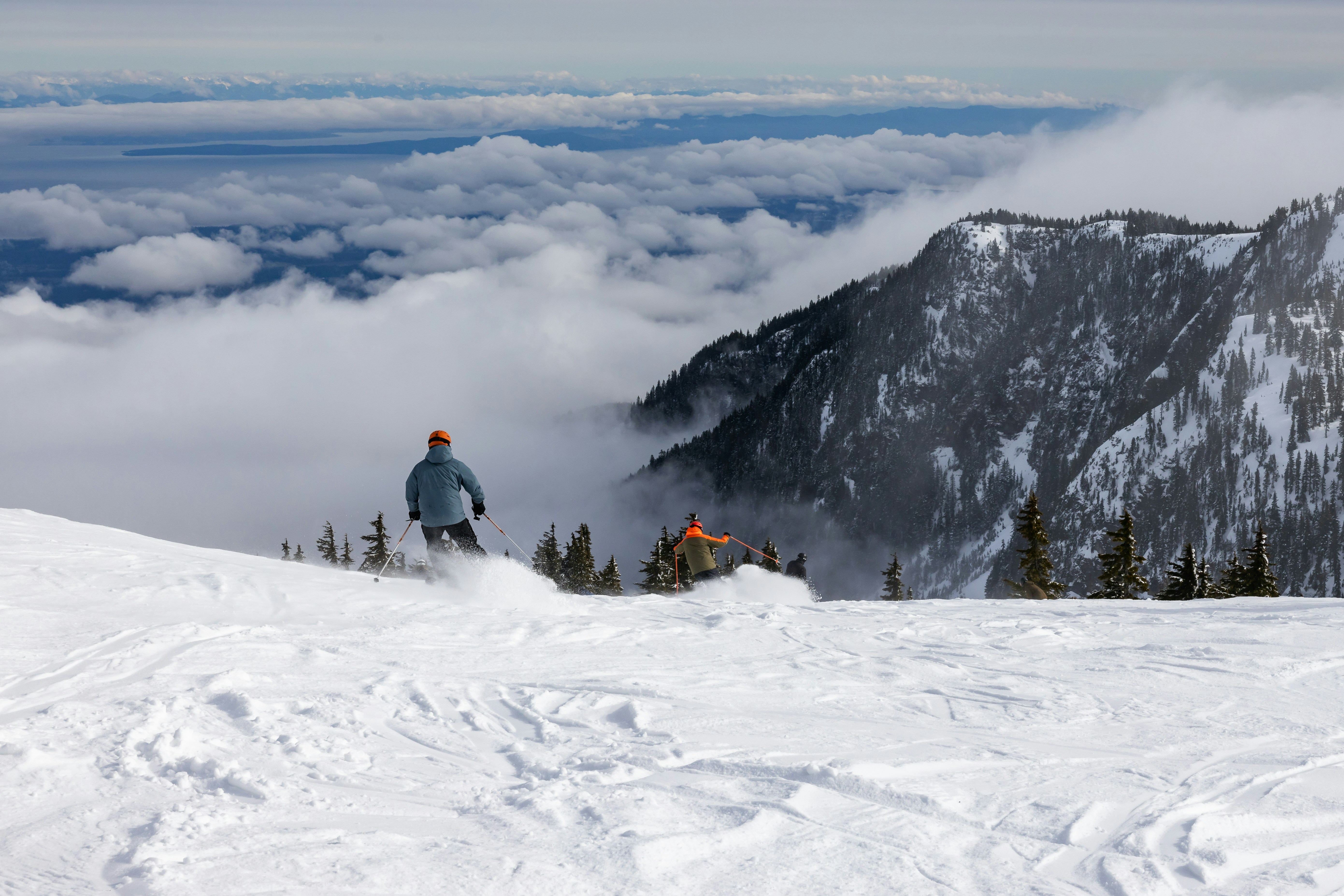 Lone hiker on a wind-swept alpine ridge above a sea of clouds
