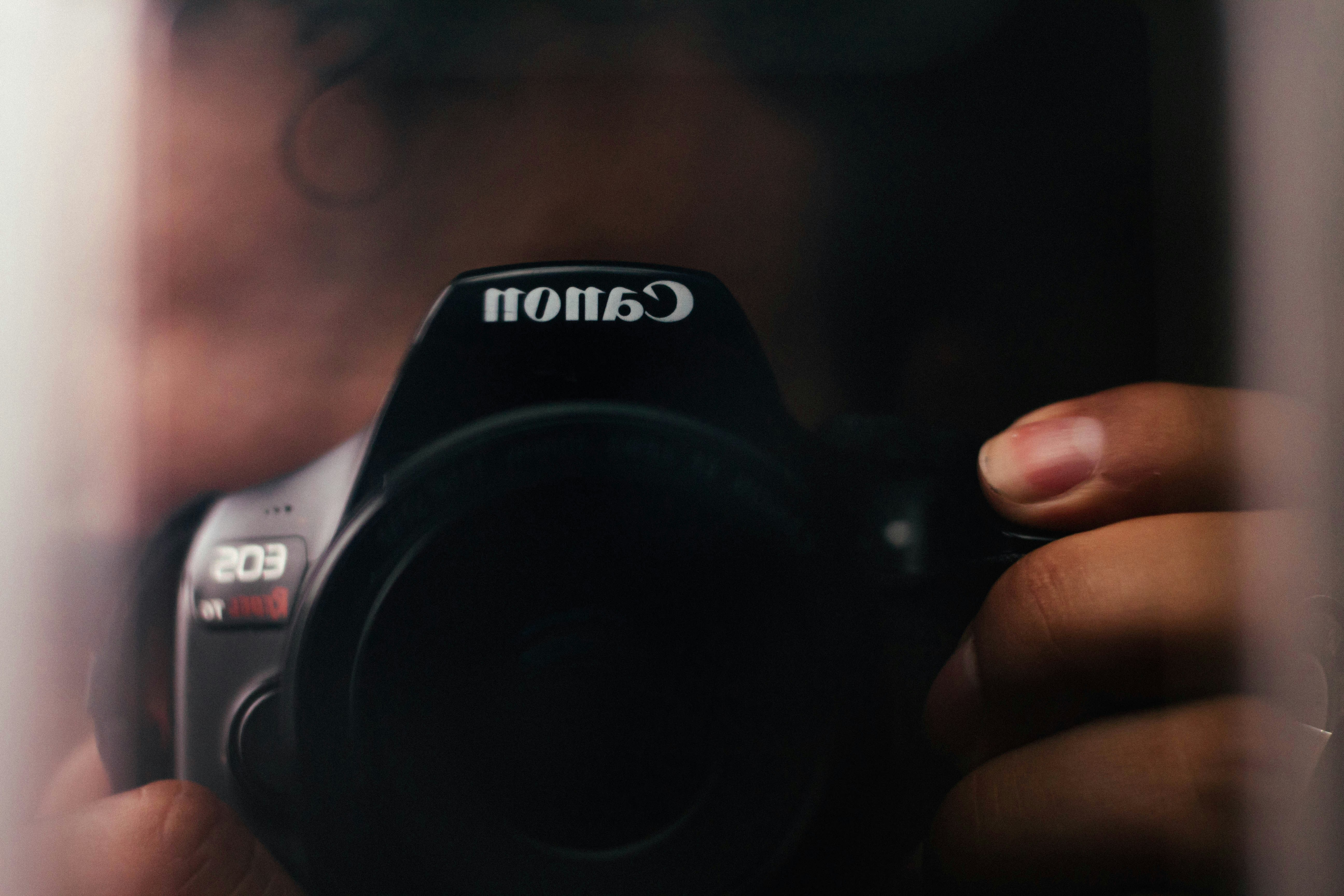 A person holding a camera up to their face photo – Free Black Image on ...