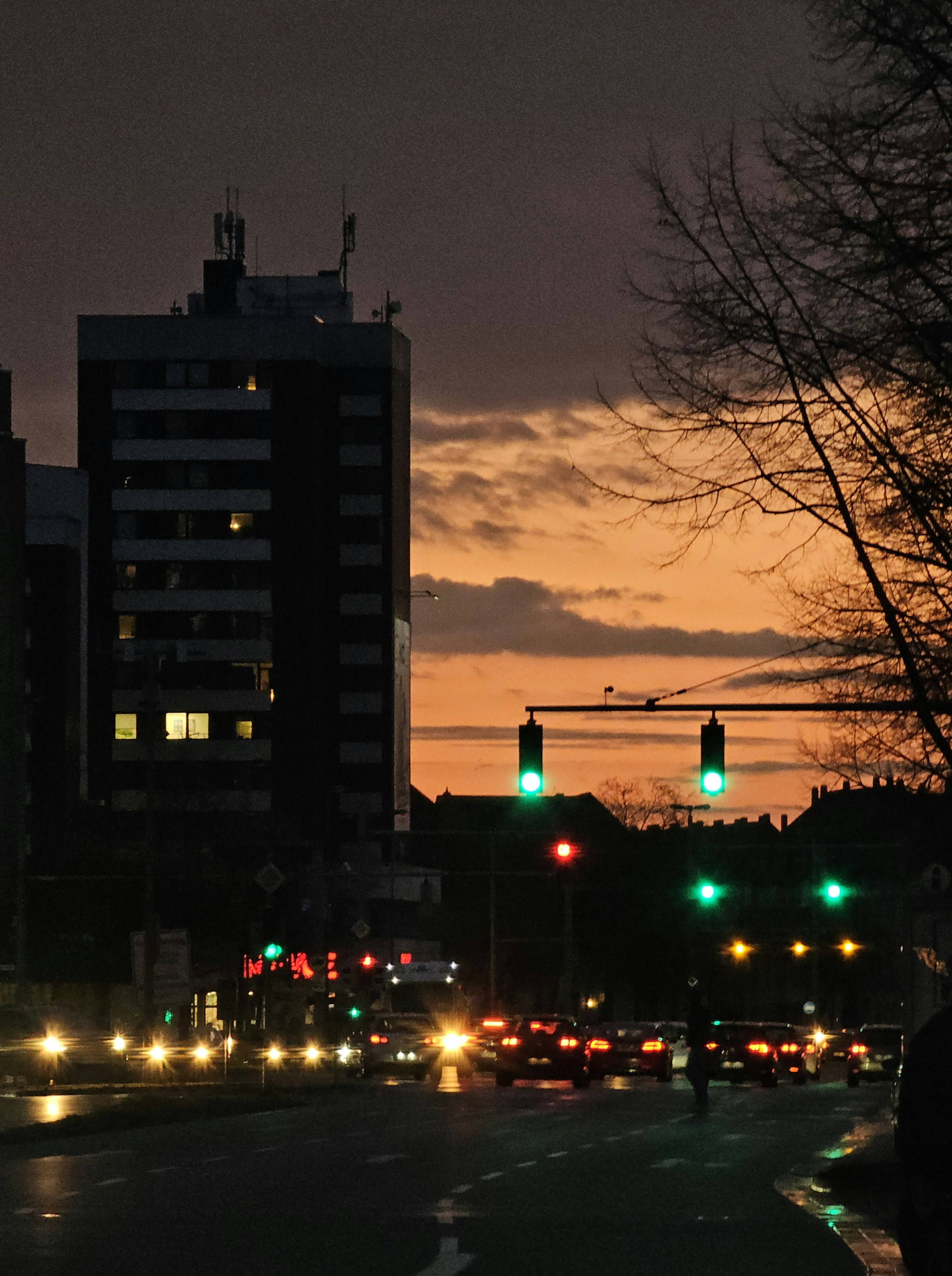 Silhouetted buildings against a vibrant twilight sky, with traffic lights illuminating the scene. The urban landscape captures the transition from day to night.