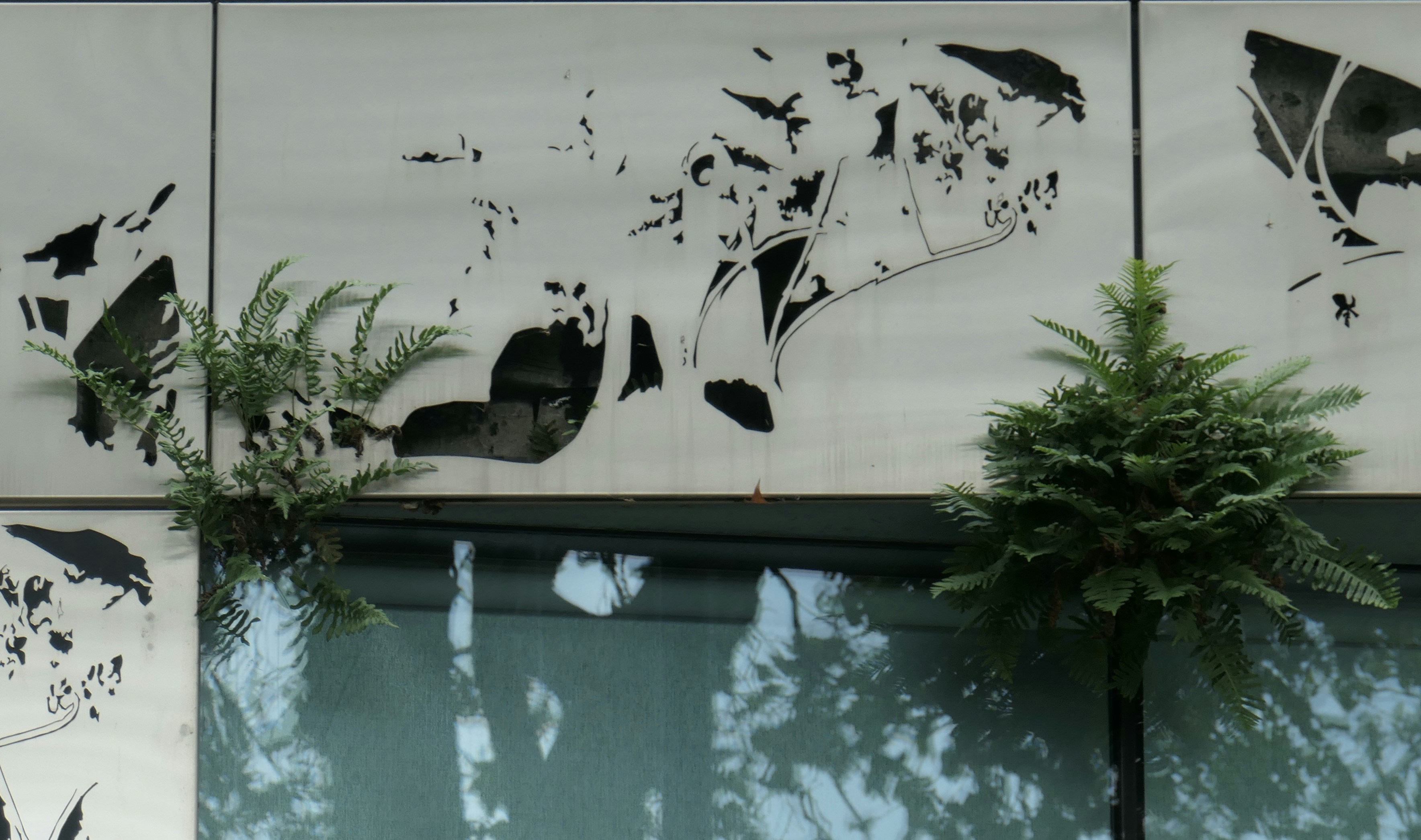 Modern building facade adorned with geometric cutouts and greenery.