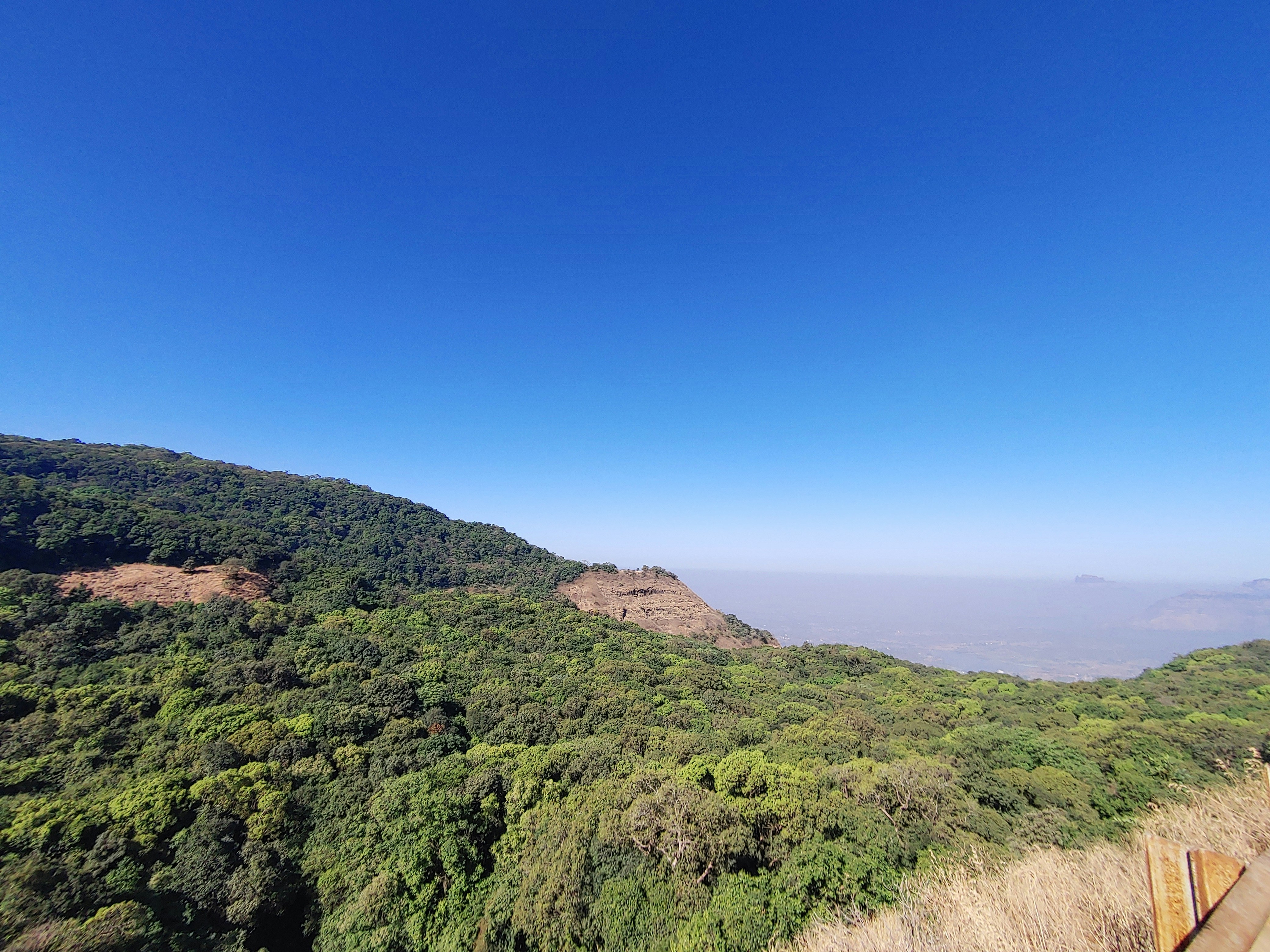 Lush green hills stretch beneath a wide expanse of clear blue sky.