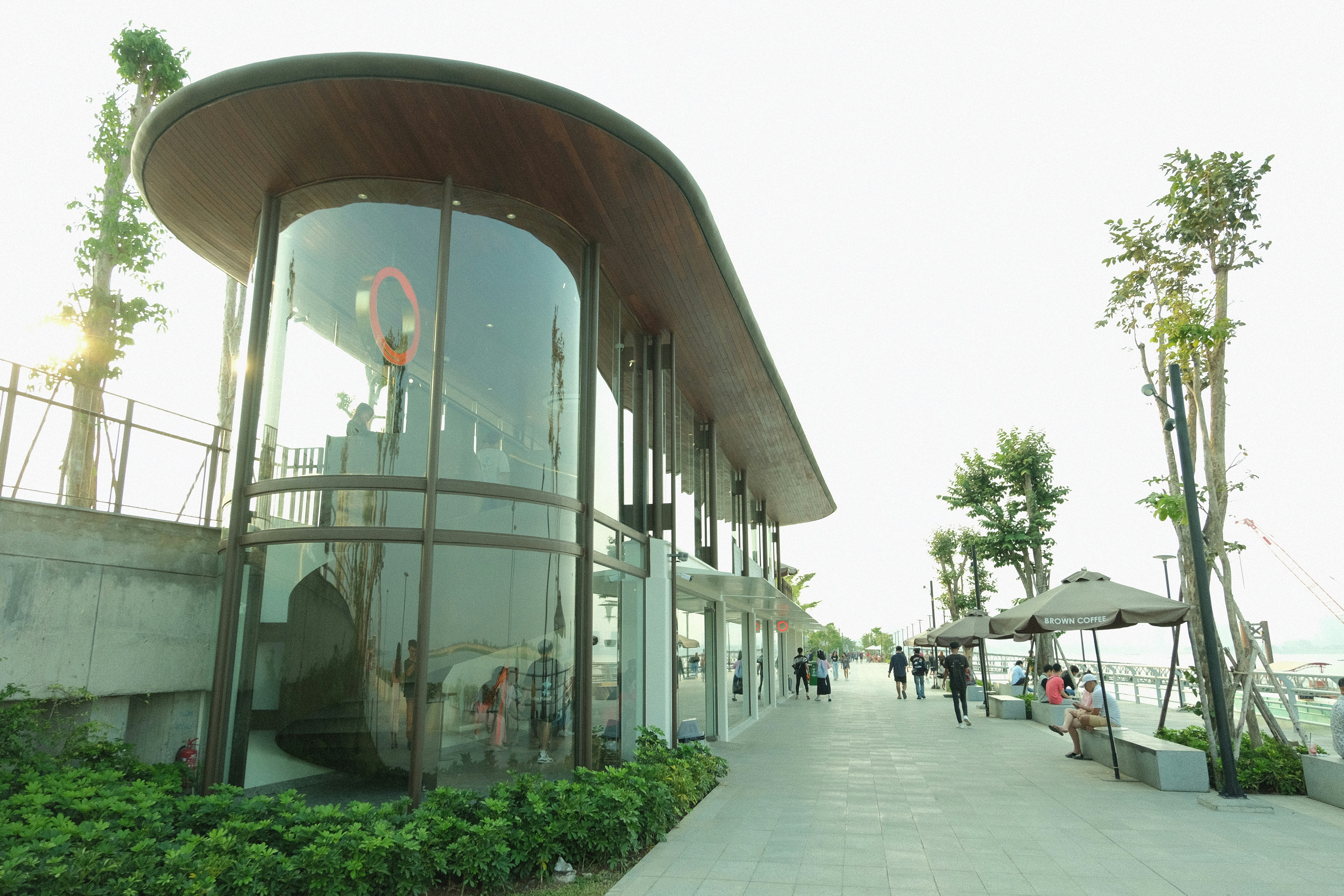 Glass Pavilion Framing a Sunlit Waterfront Promenade