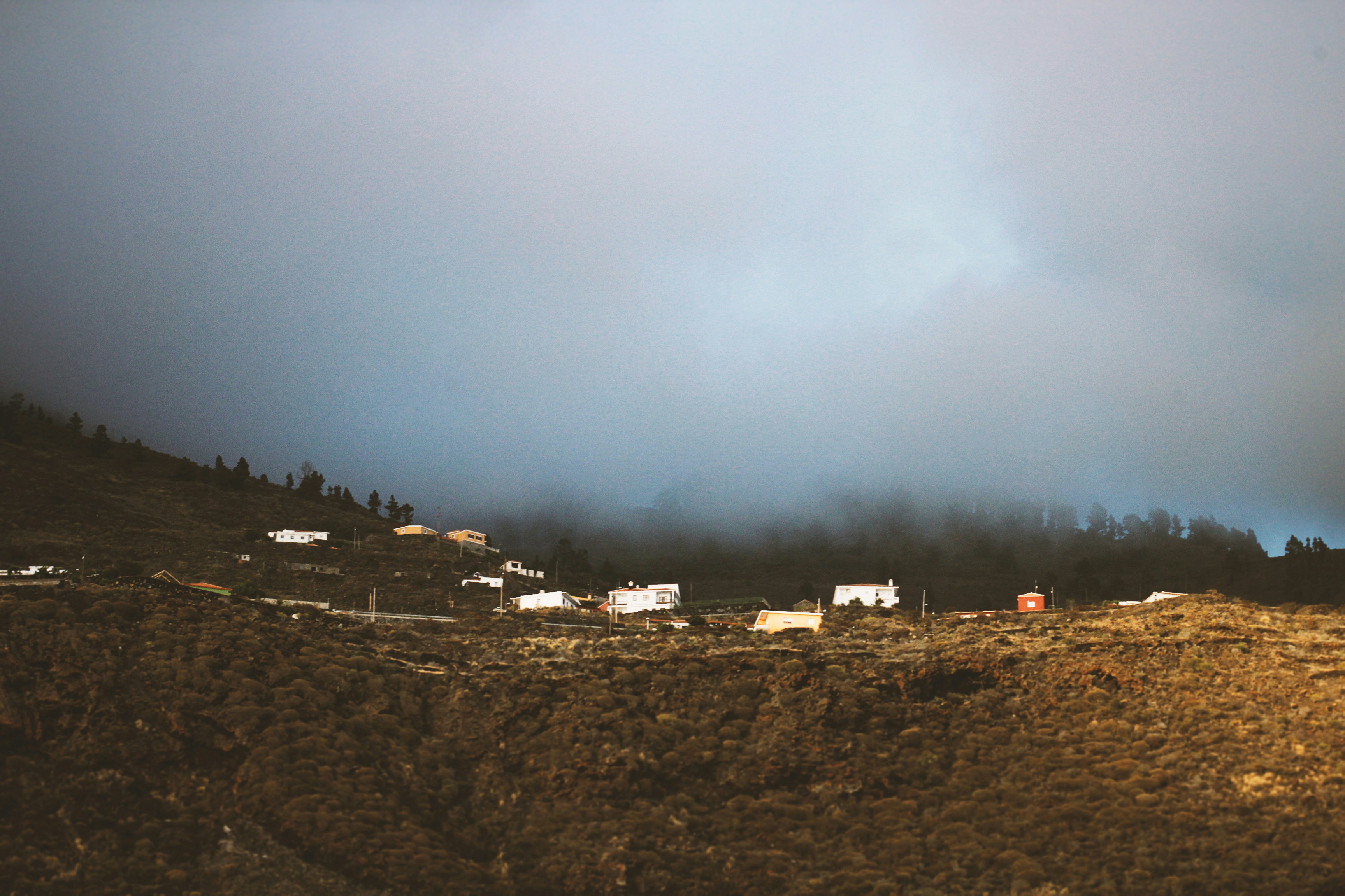 Hushed hillside village under a moody cloudscape