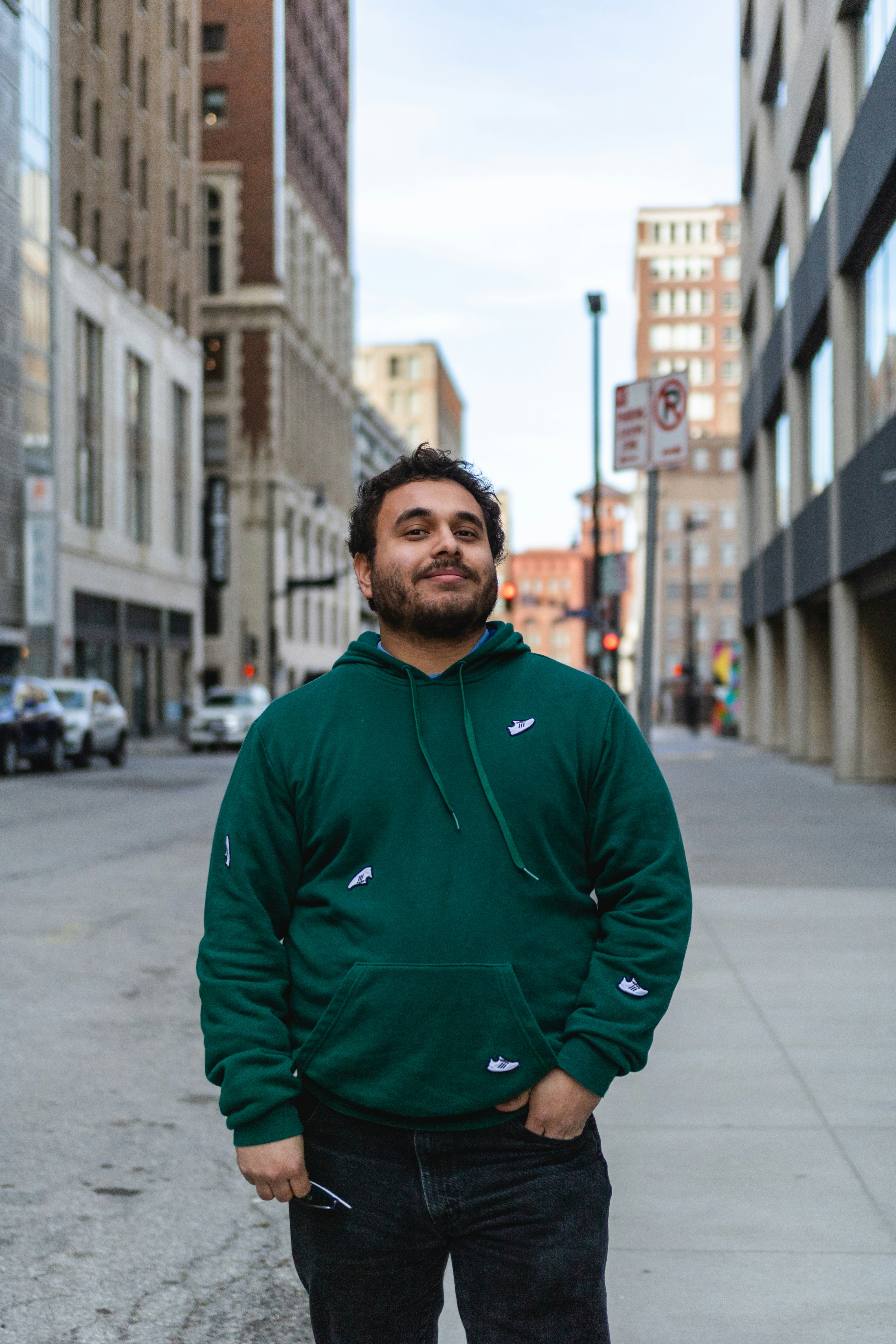 Midtown Focus: Portrait of a Man in a Green Hoodie Amid Concrete Canyons