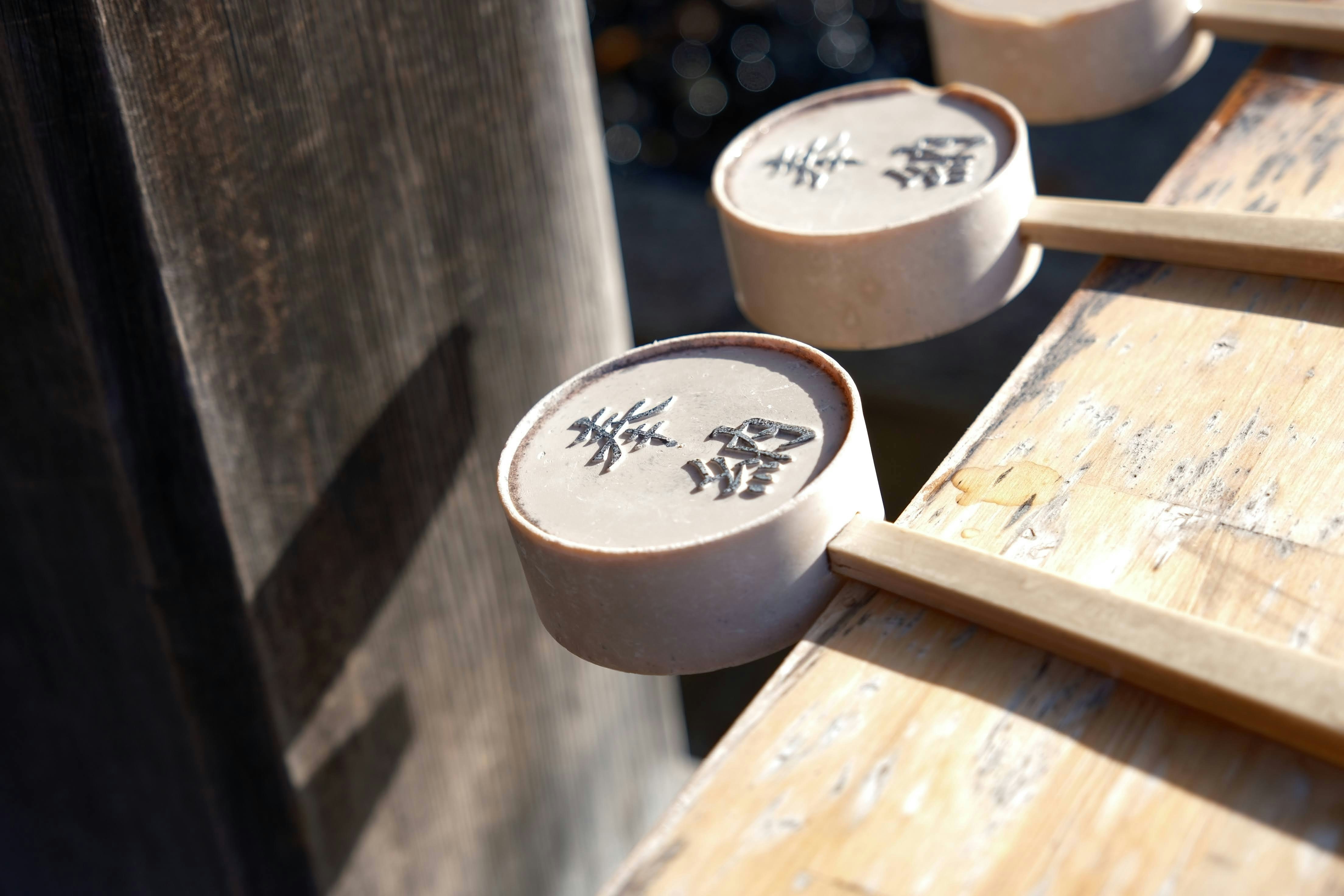 Sunlit Rounds: Calligraphy-Capped Wooden Discs on Weathered Planks