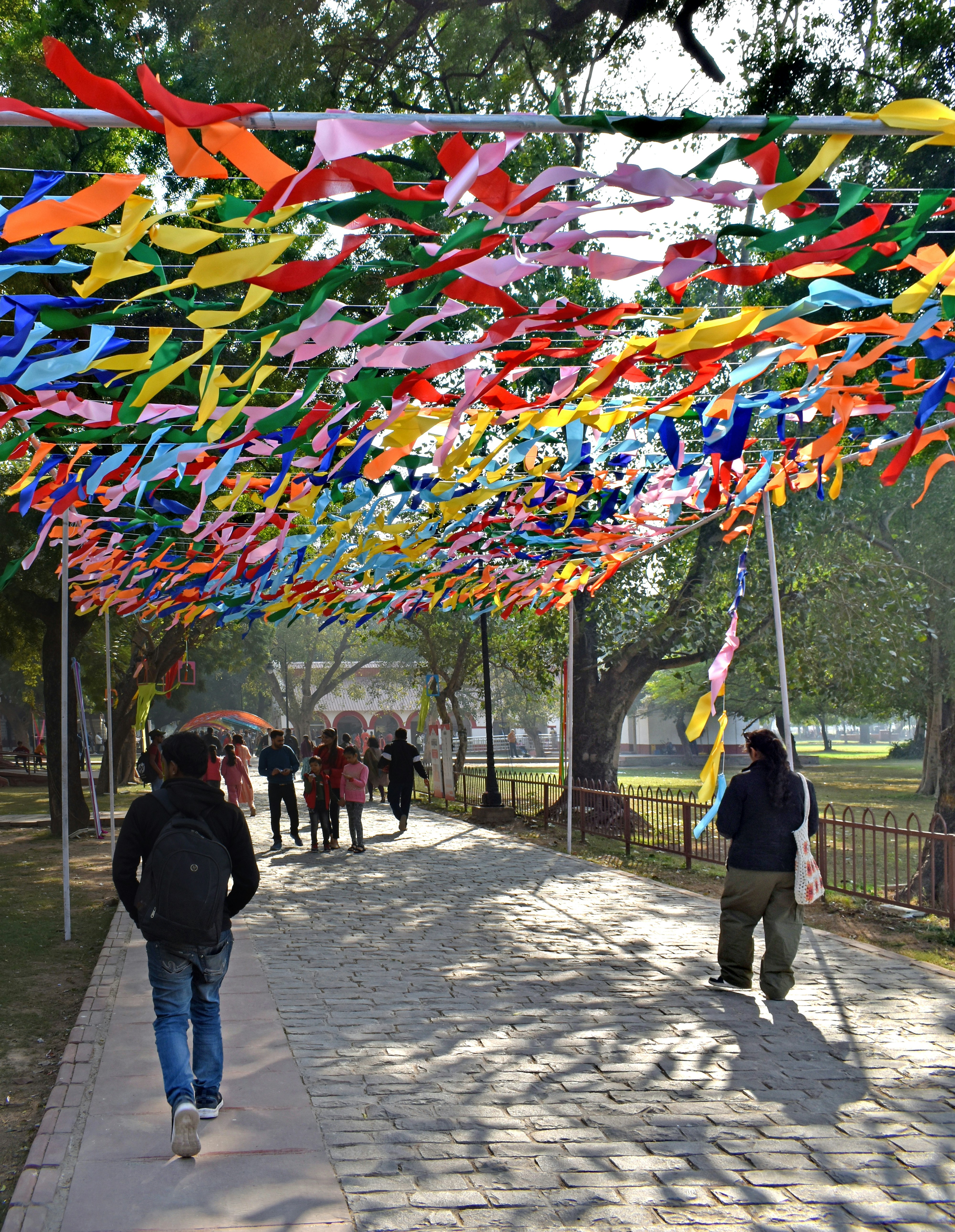 A group of people walking down a sidewalk under a canopy of colorful ...