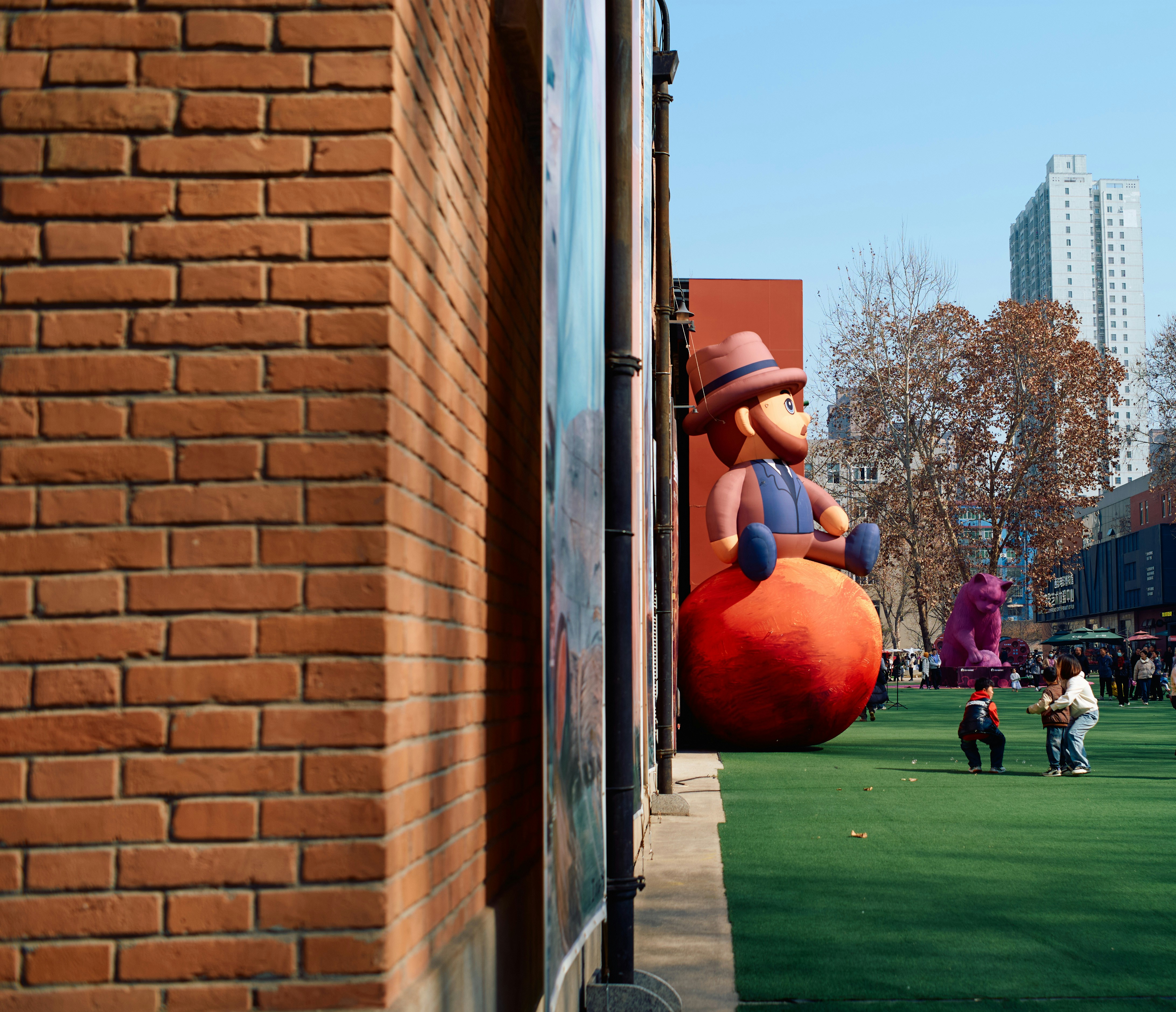 Whimsical Orange Sentinel: Plush Sculpture Guards a Green Plaza