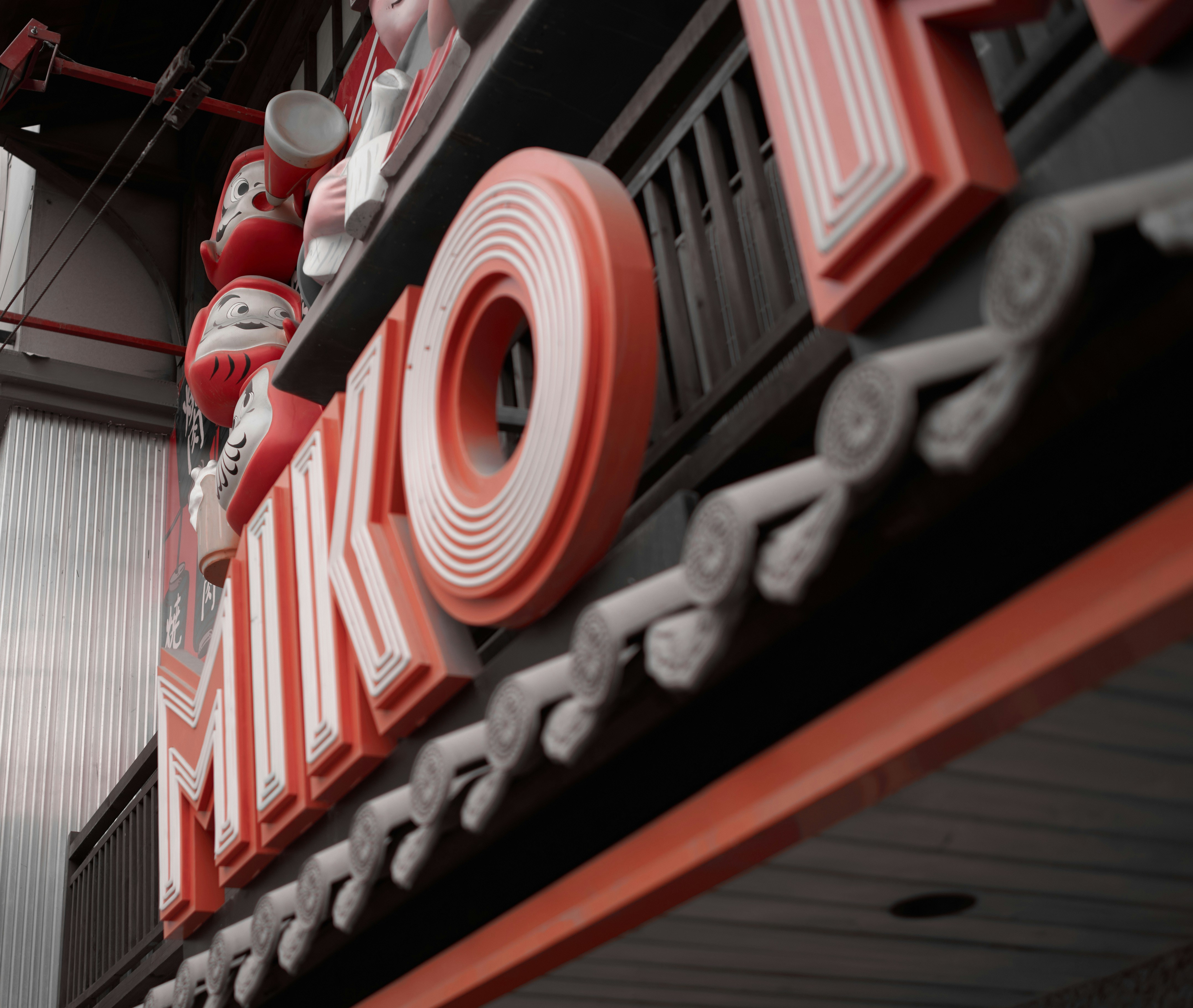 Bold red letters on a building facade with traditional roof elements and decorative figures.