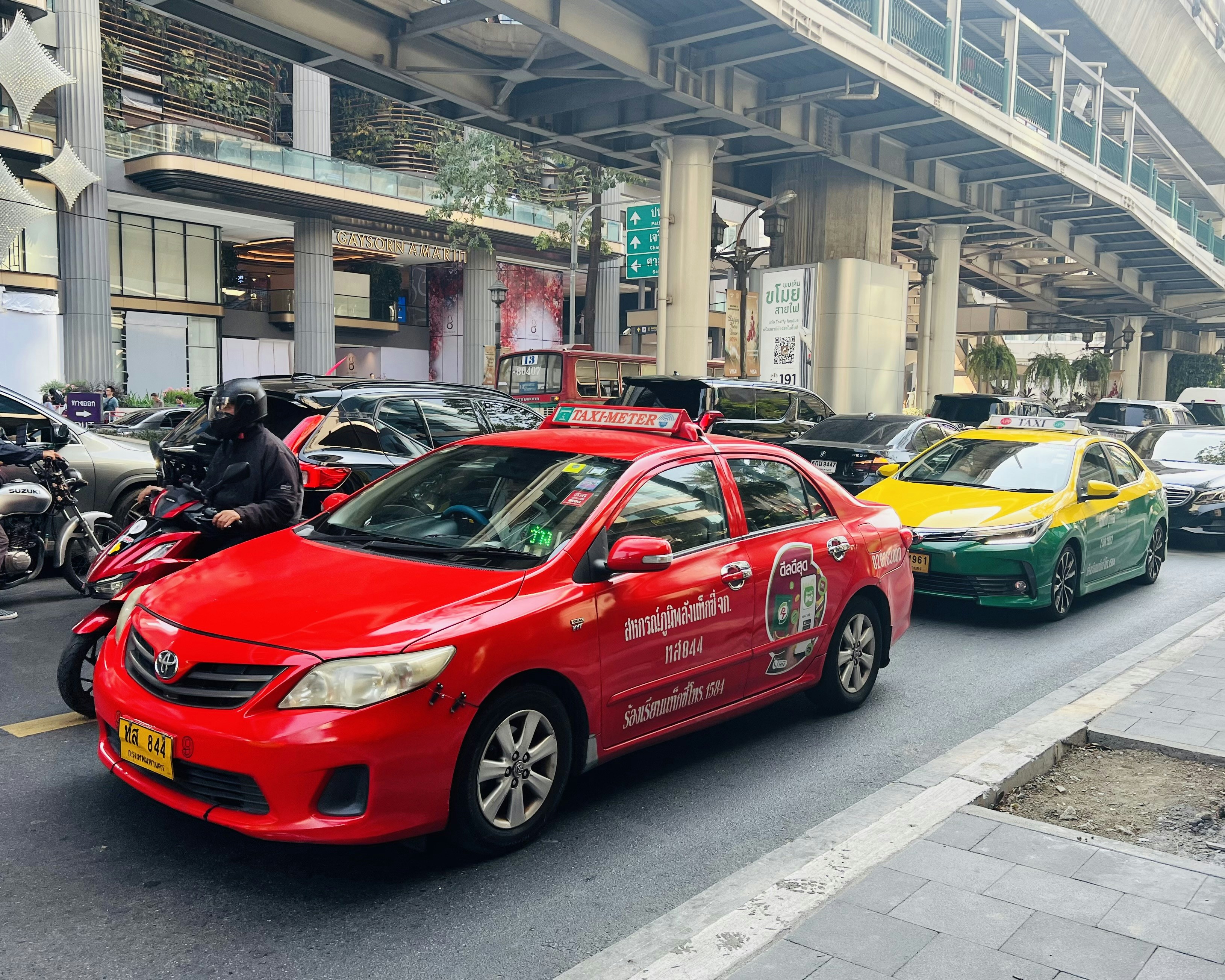 A red taxi cab driving down a street next to tall buildings photo ...
