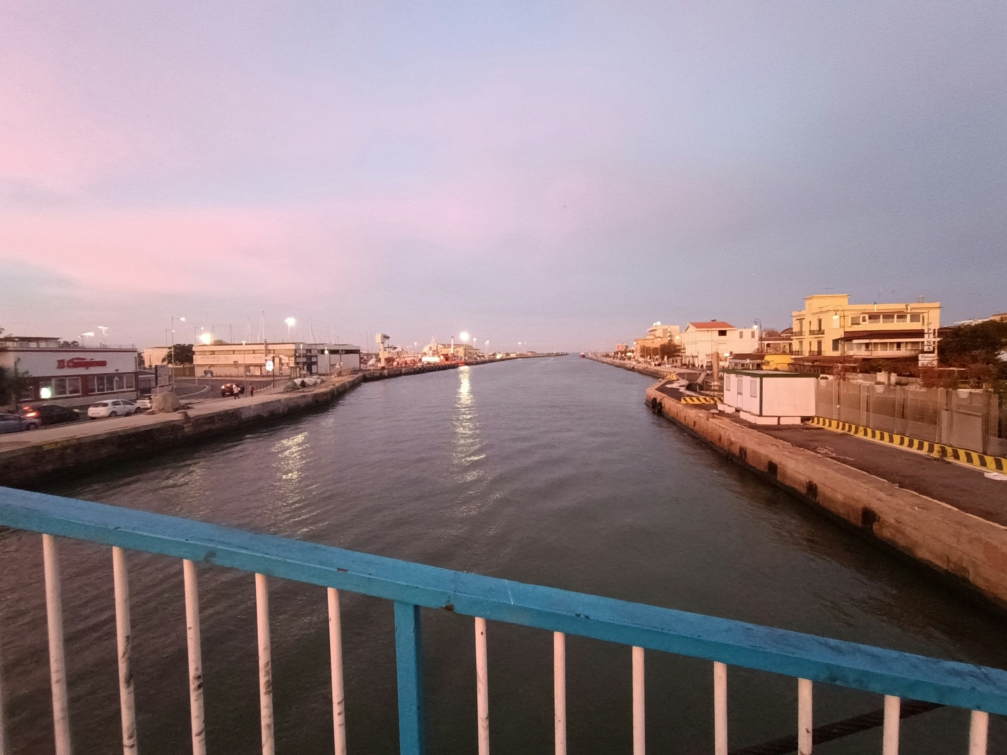 Tranquil river flanked by industrial buildings under a pastel sky at dusk.
