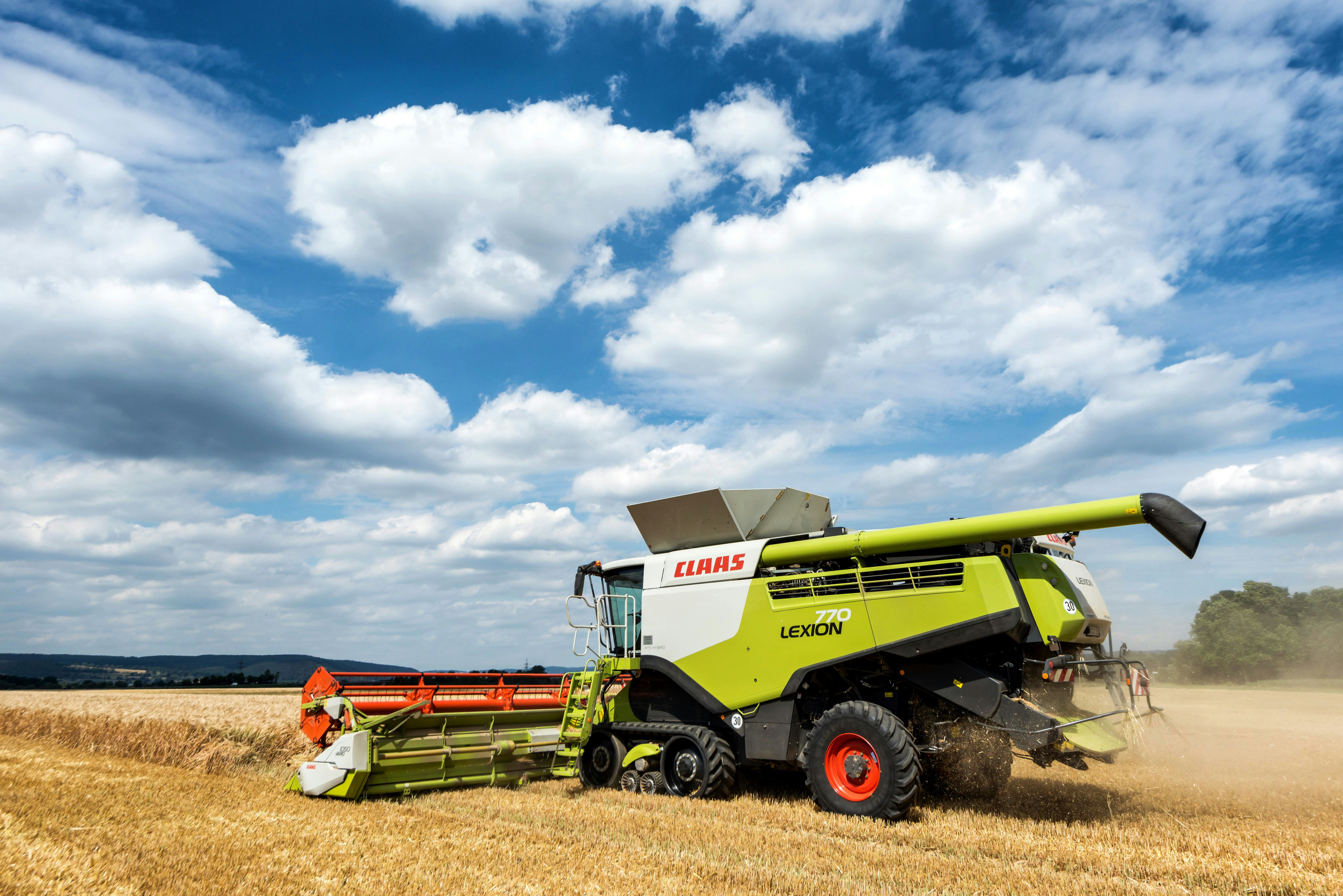 A green and white combine truck driving through a wheat field photo ...