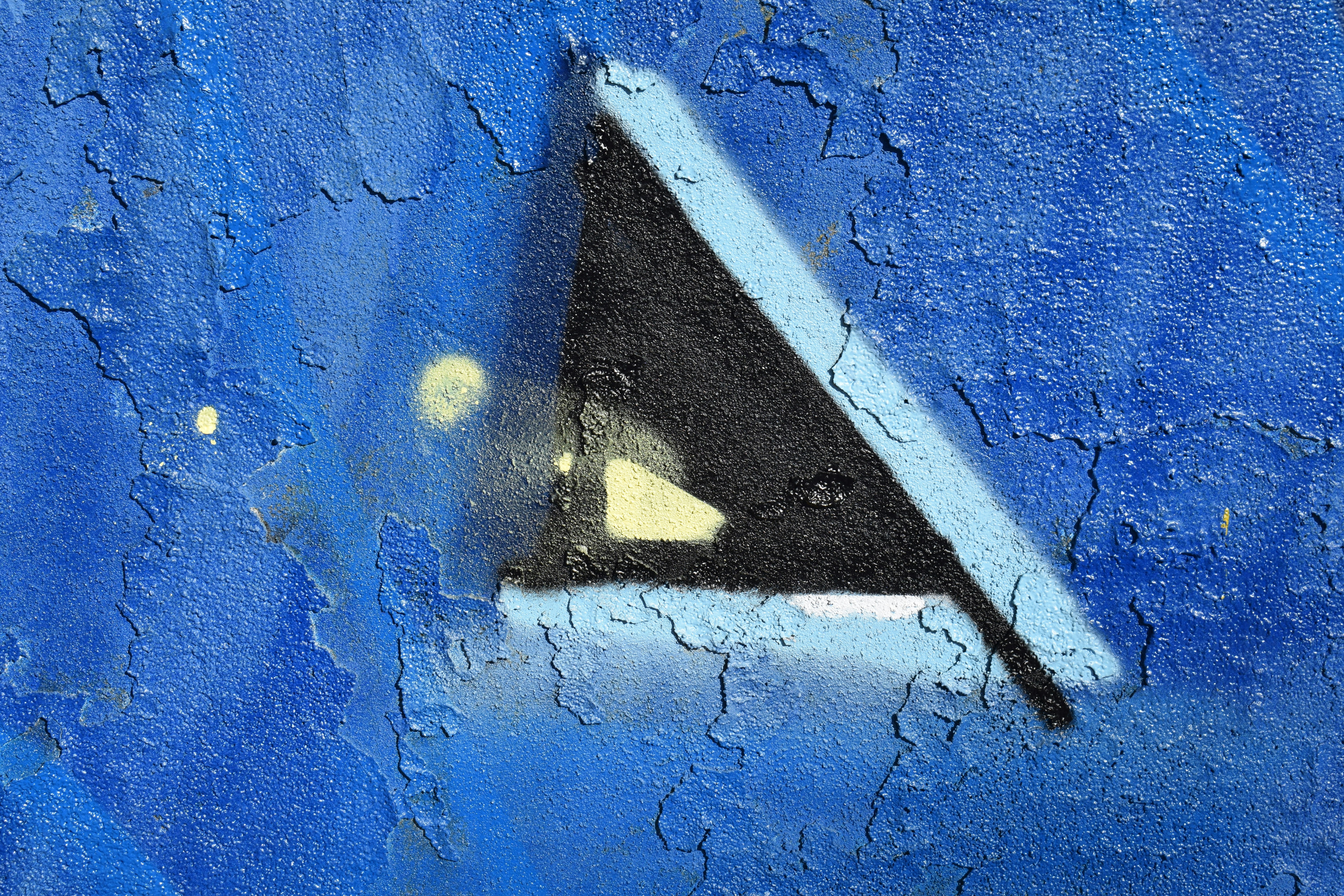 Azure Graffiti Triangle: A Cracked Warning on Peeling Paint