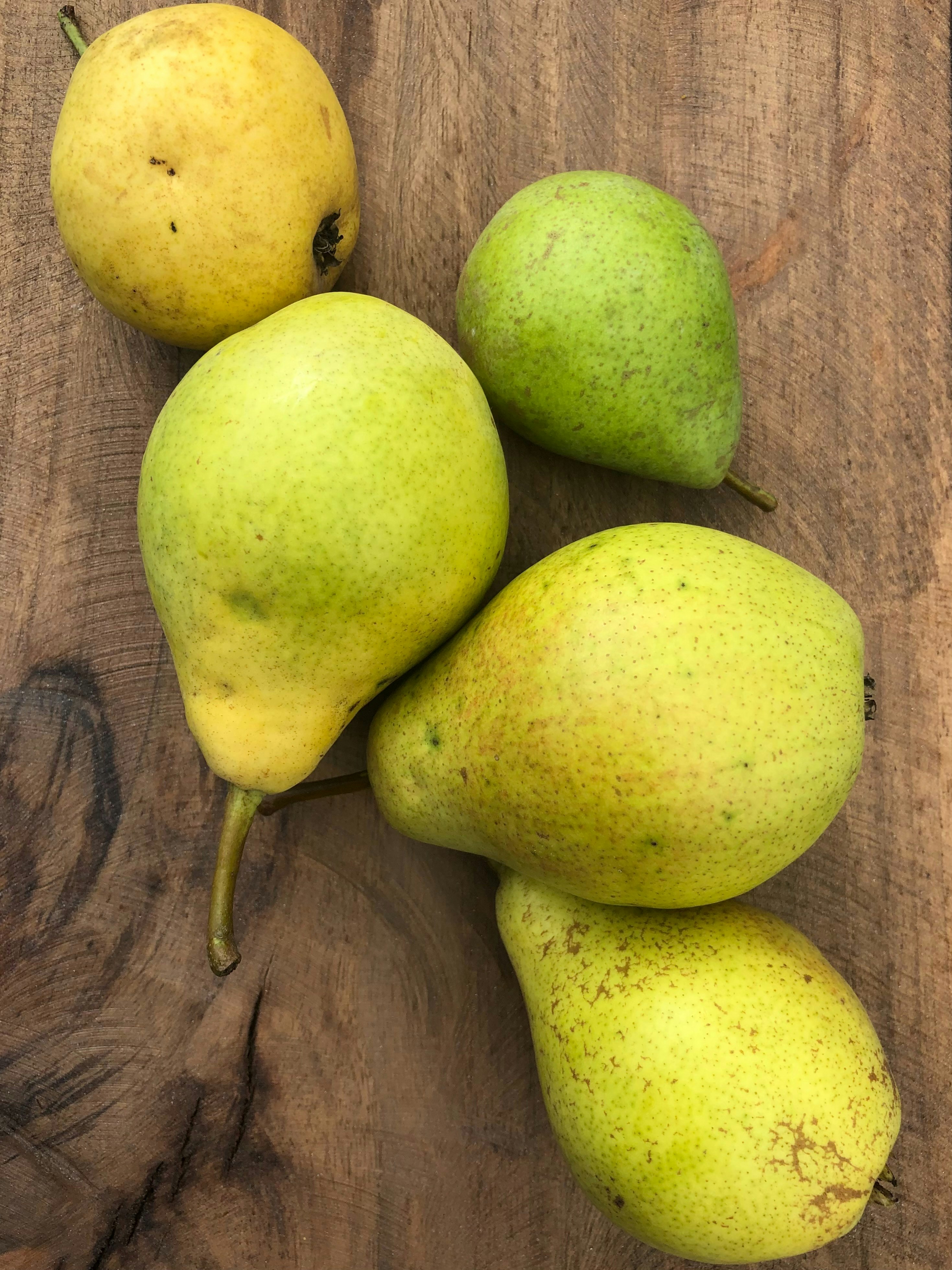 a pile of pears sitting on top of a wooden table