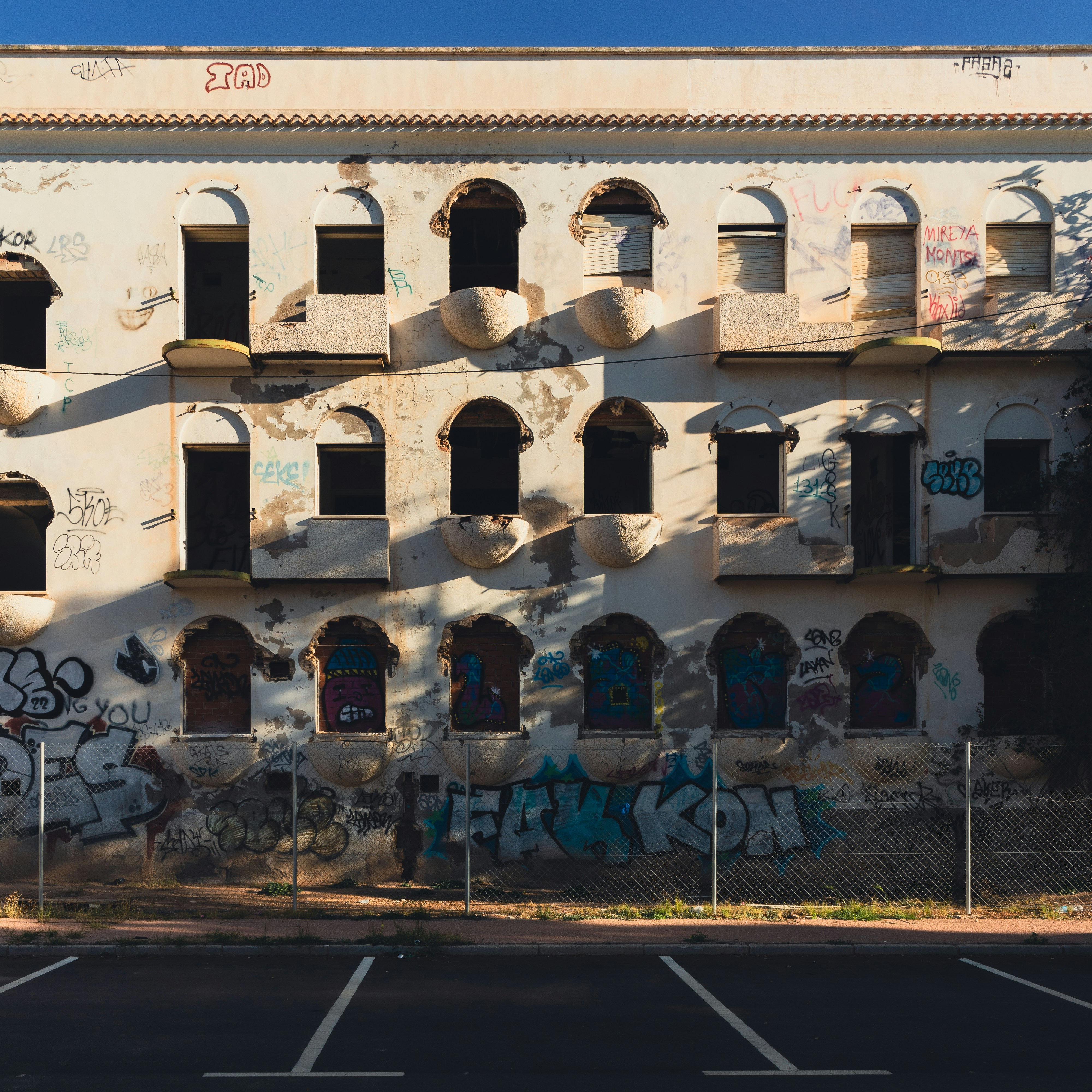 Graffiti-Vaulted Facade: Sunlit Arches and Shifting Shadows