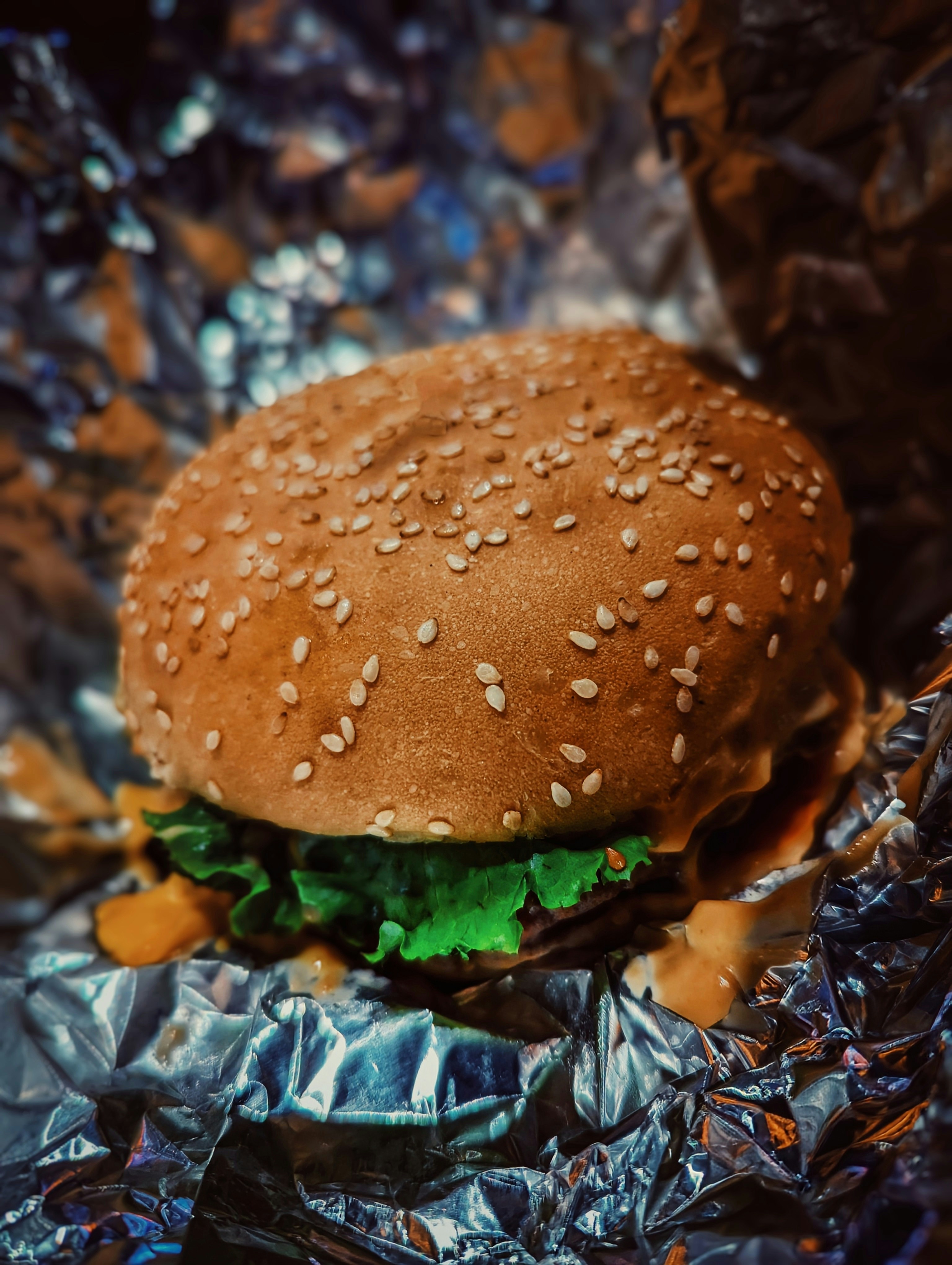 A close up shot of a burger inside a tinfoil wrapper