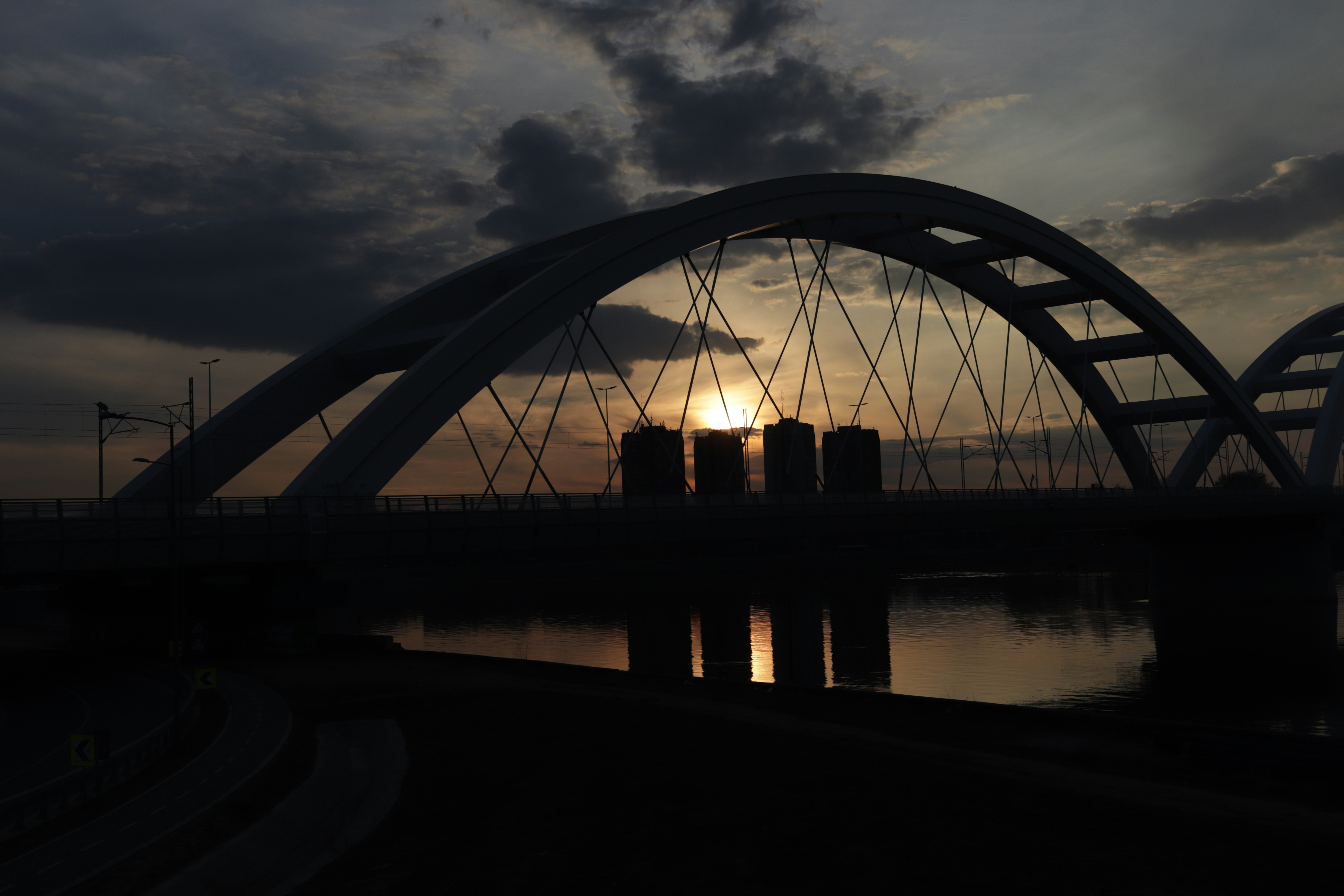 Dusk Over the Arc: A Bridge Silhouette Against a Glowing Skyline