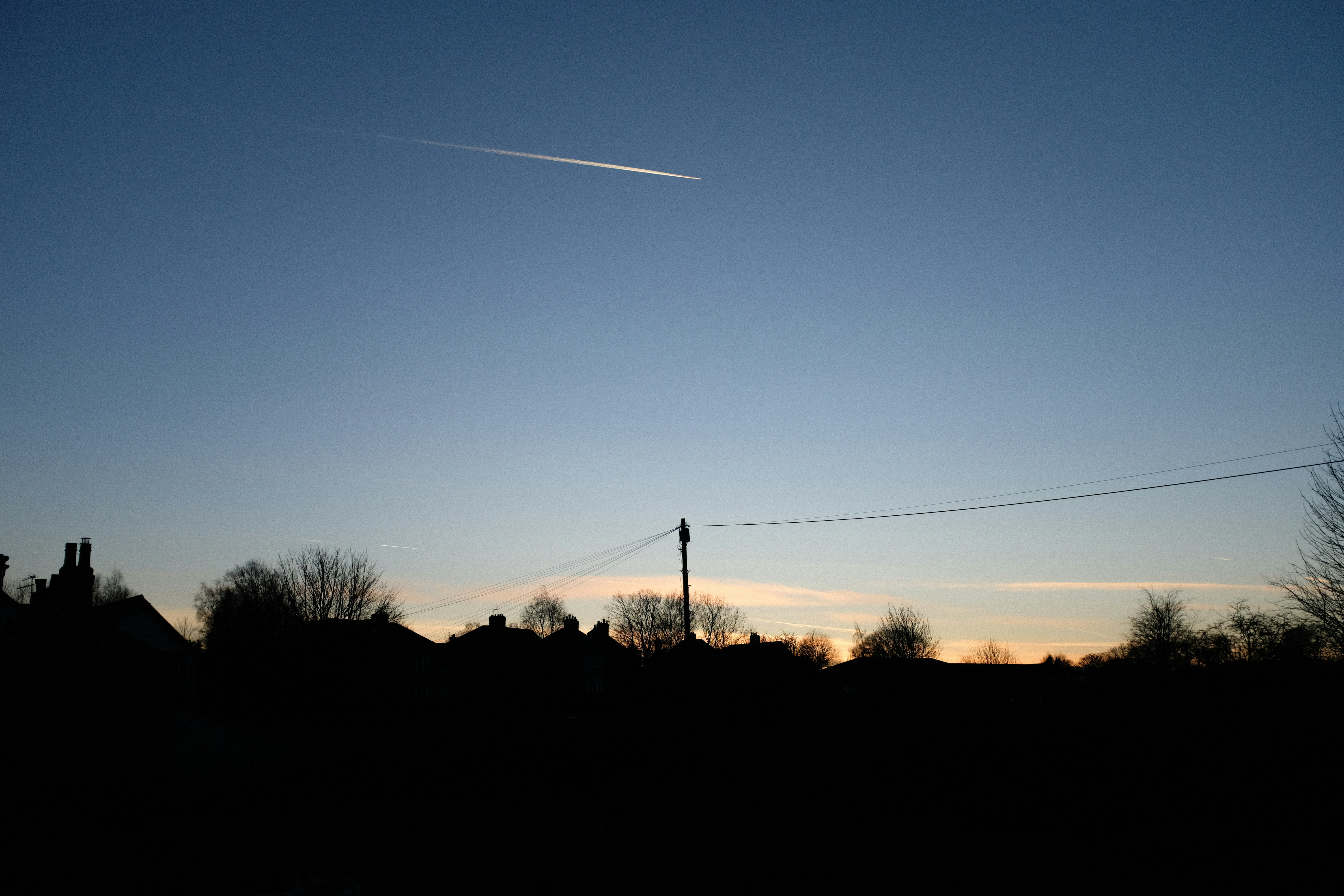 Blue Hour Contrail Skims a Silhouette of a Quiet Village