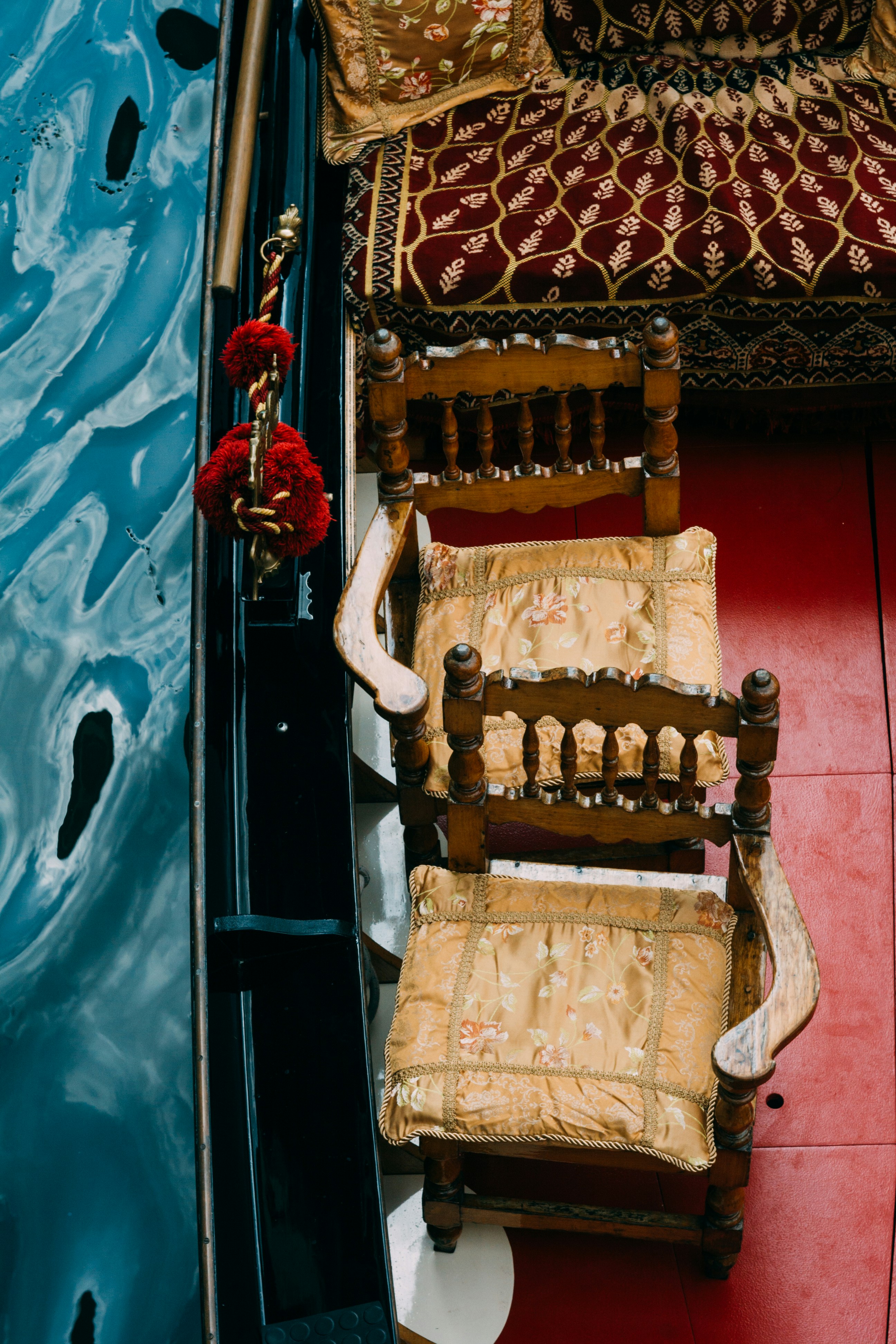 Hullside Velvet: Vintage Chairs and Floral Cushions on a Crimson Deck