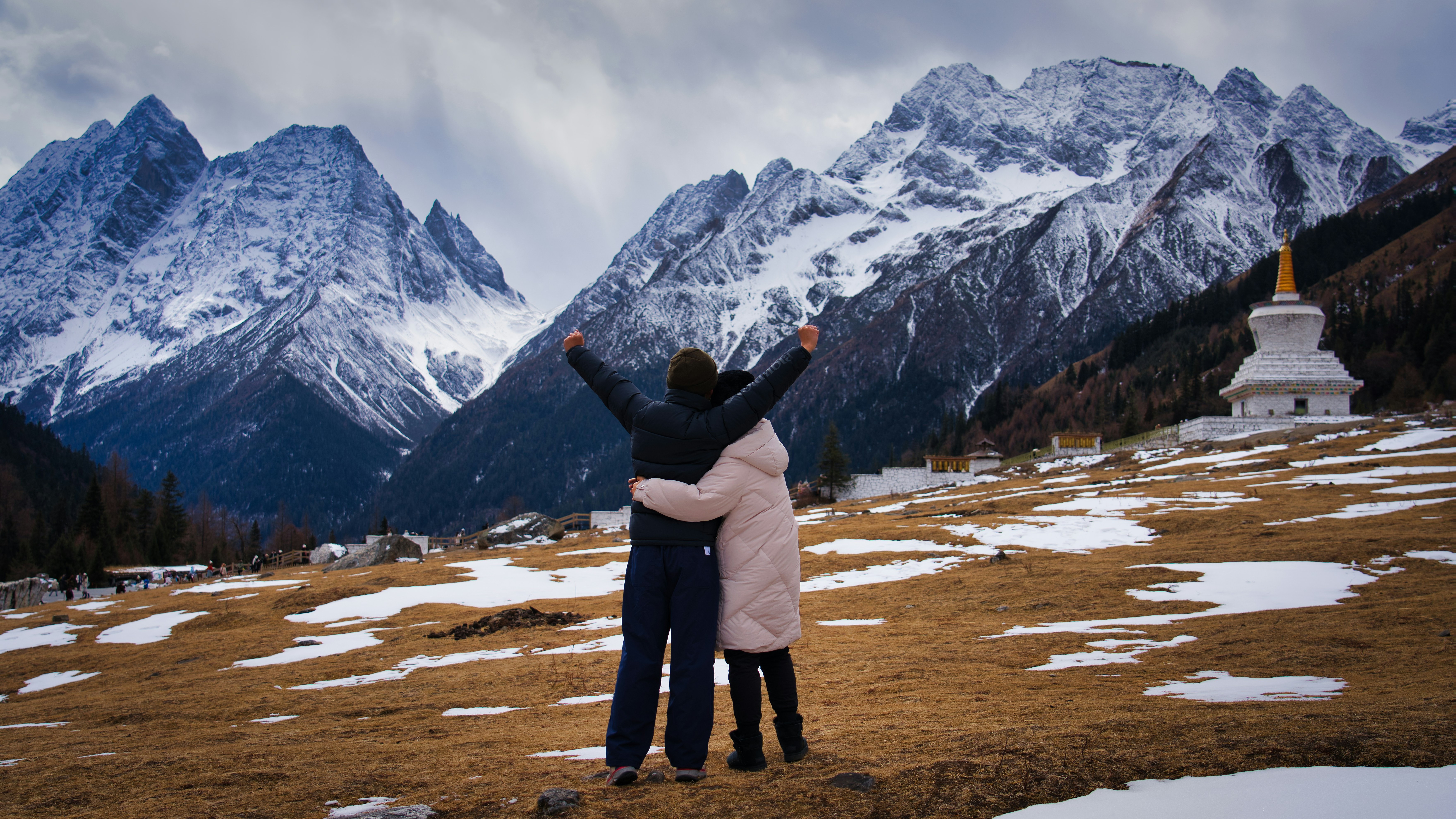 Embrace on an Alpine Plain Beneath Snowy Peaks and a Quiet Stupa