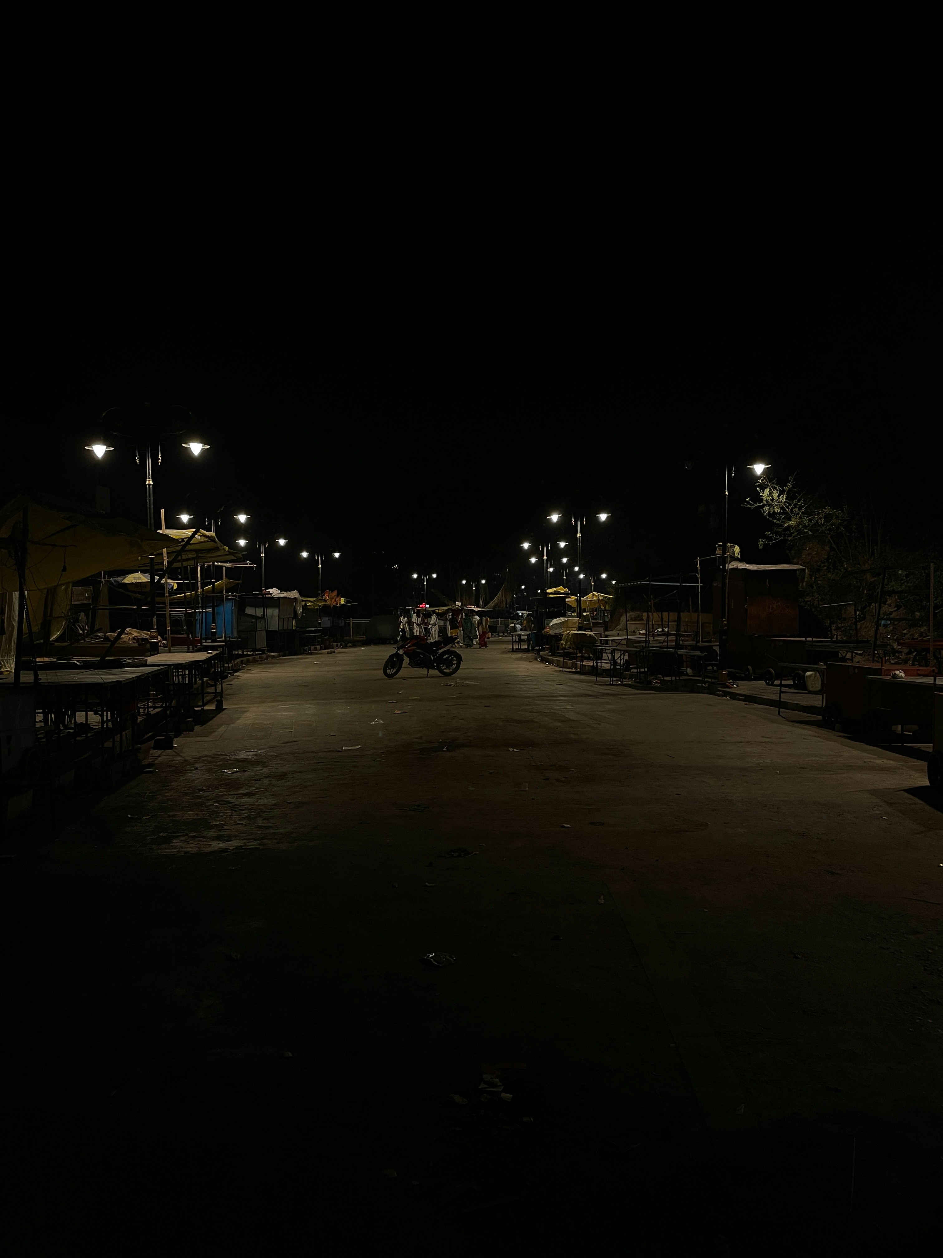 The photo captures the bustling streets of Ujjain, resonating with a blend of ancient charm and modern life. Narrow lanes adorned with vibrant stalls and shops showcase the city's rich cultural tapestry. Pilgrims and locals alike move along the lively street, passing by traditional architecture and contemporary elements. The ambiance is filled with the sounds of daily life, creating a vivid snapshot of the dynamic and diverse street scenes in the heart of Ujjain.