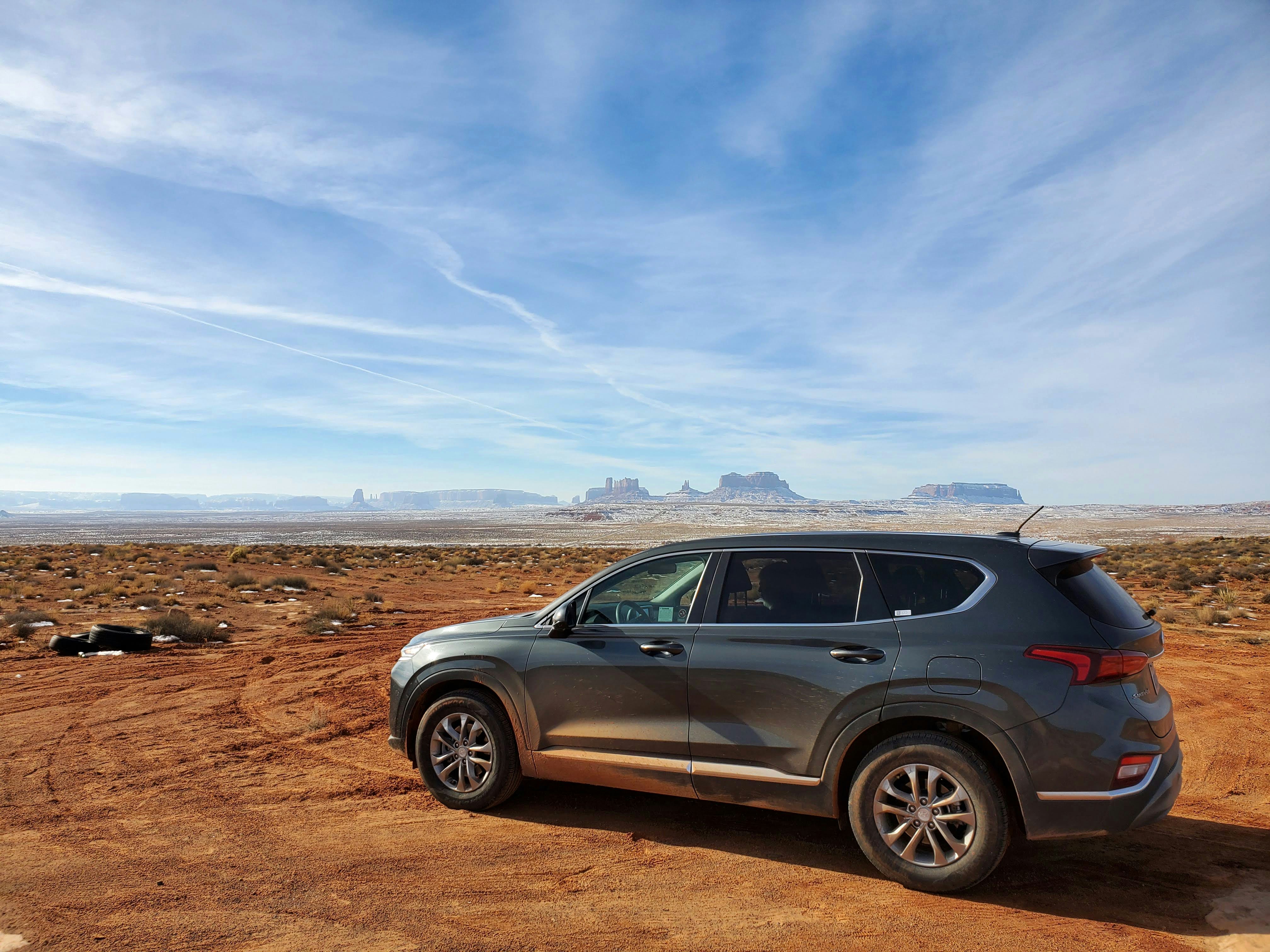 Silver SUV on a Rust-Red Desert Stage Beneath a Vast Blue Sky