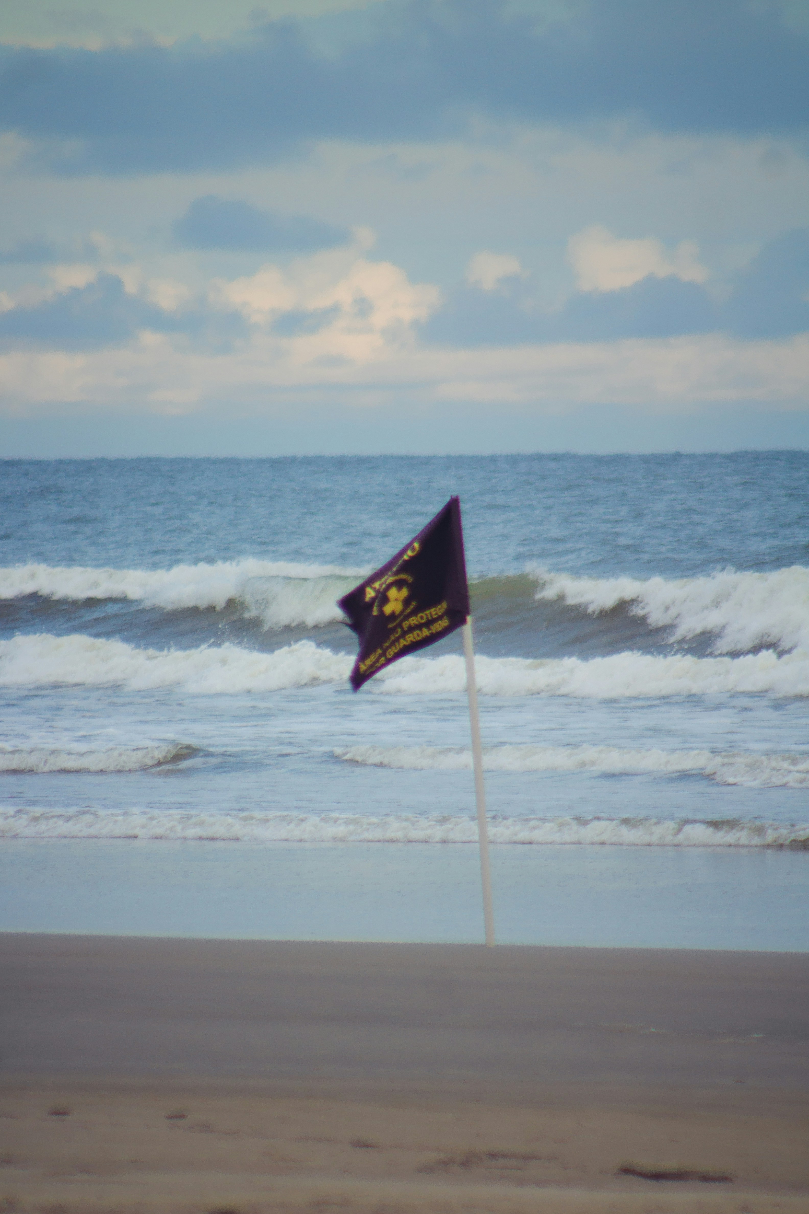 Flag in the surf: a lone purple pennant marks the shore