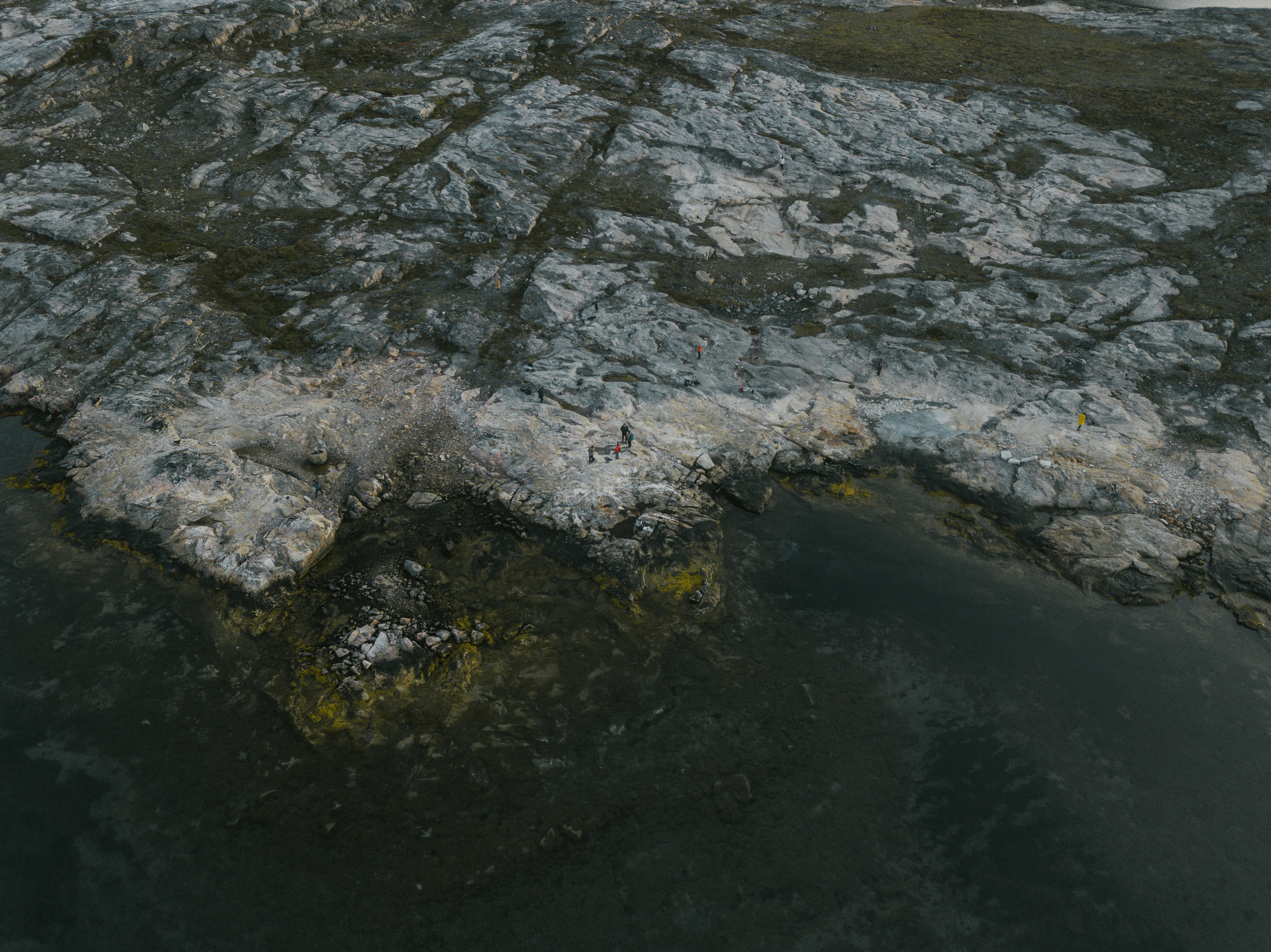 Granite Edge Ballet: Tiny Figures on a Sea-Sculpted Shore