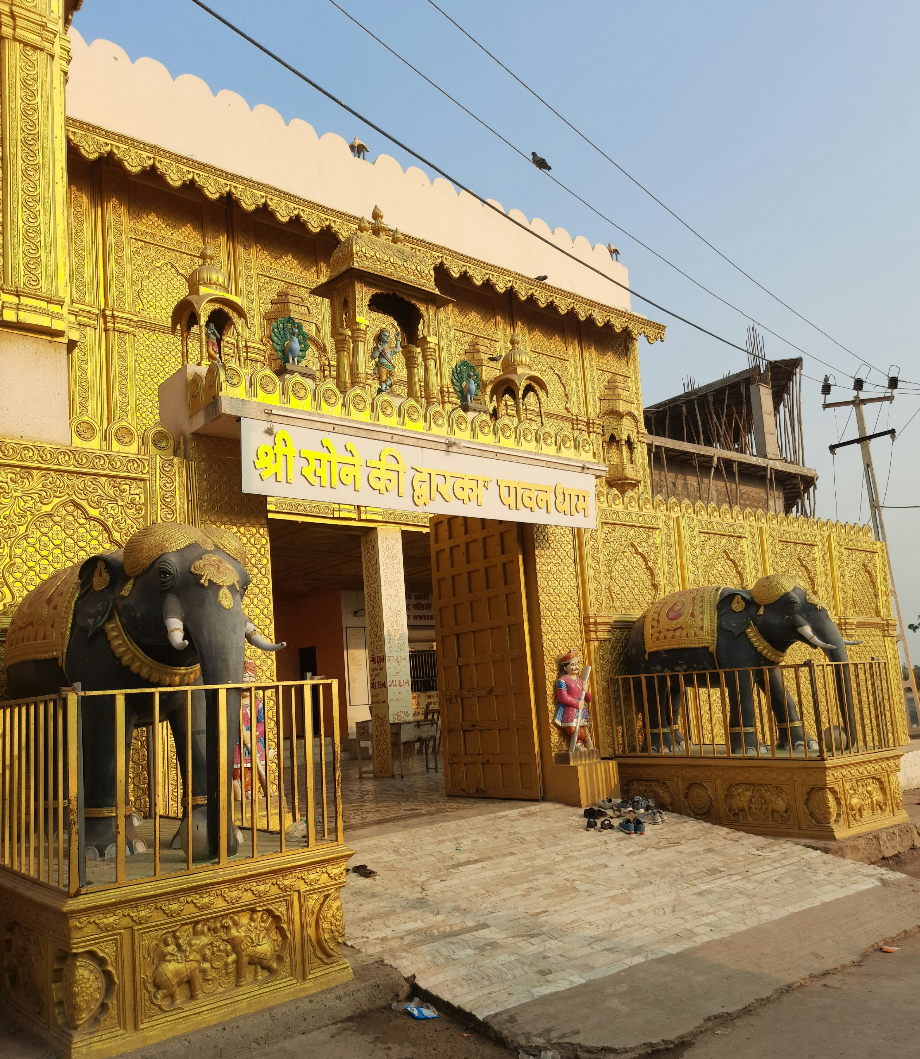 Gilded Gateway: Elephants Guarding a Sunlit Temple Entrance