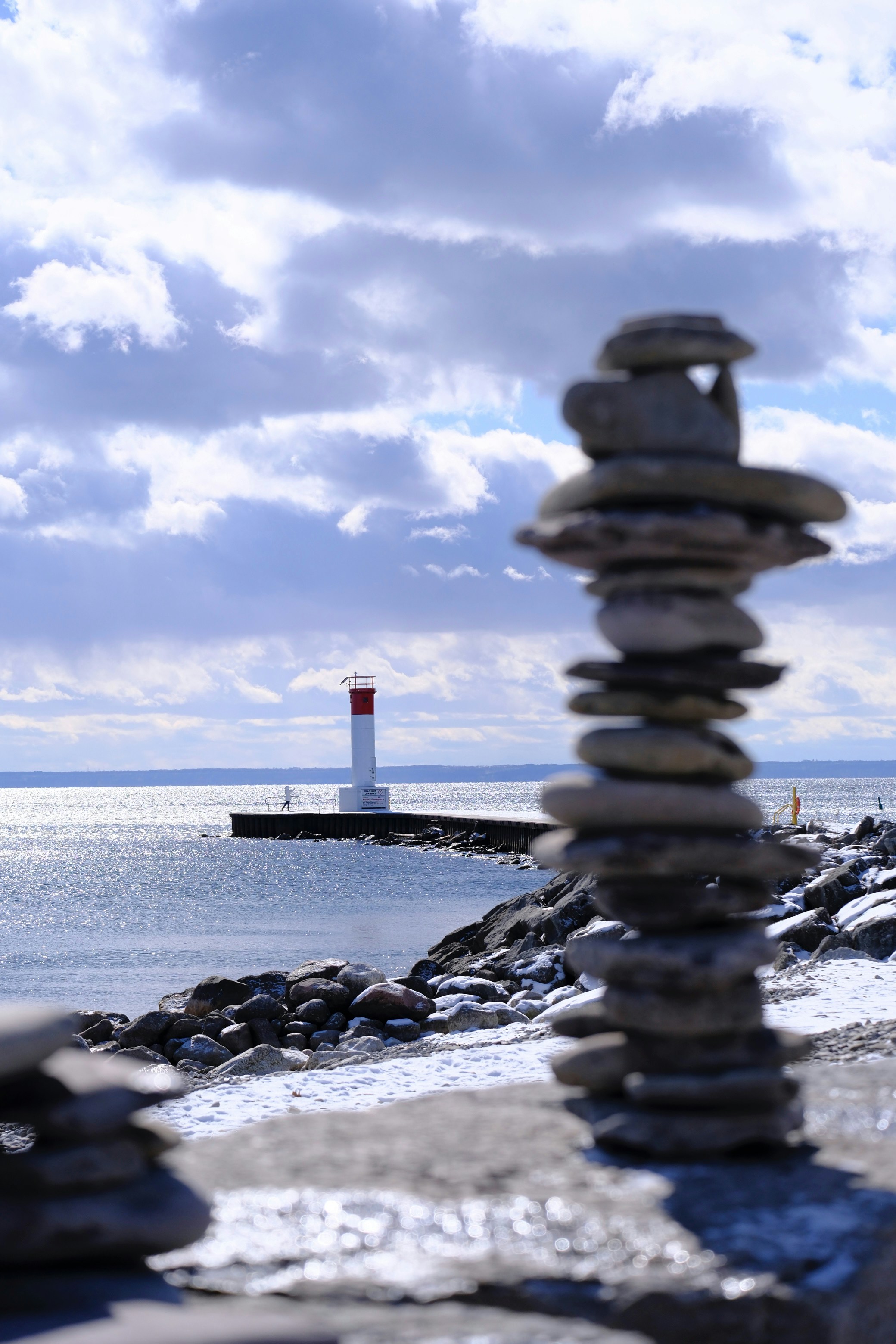 Lighthouse Through a Tower of Stones: A Quiet Breakwater Moment