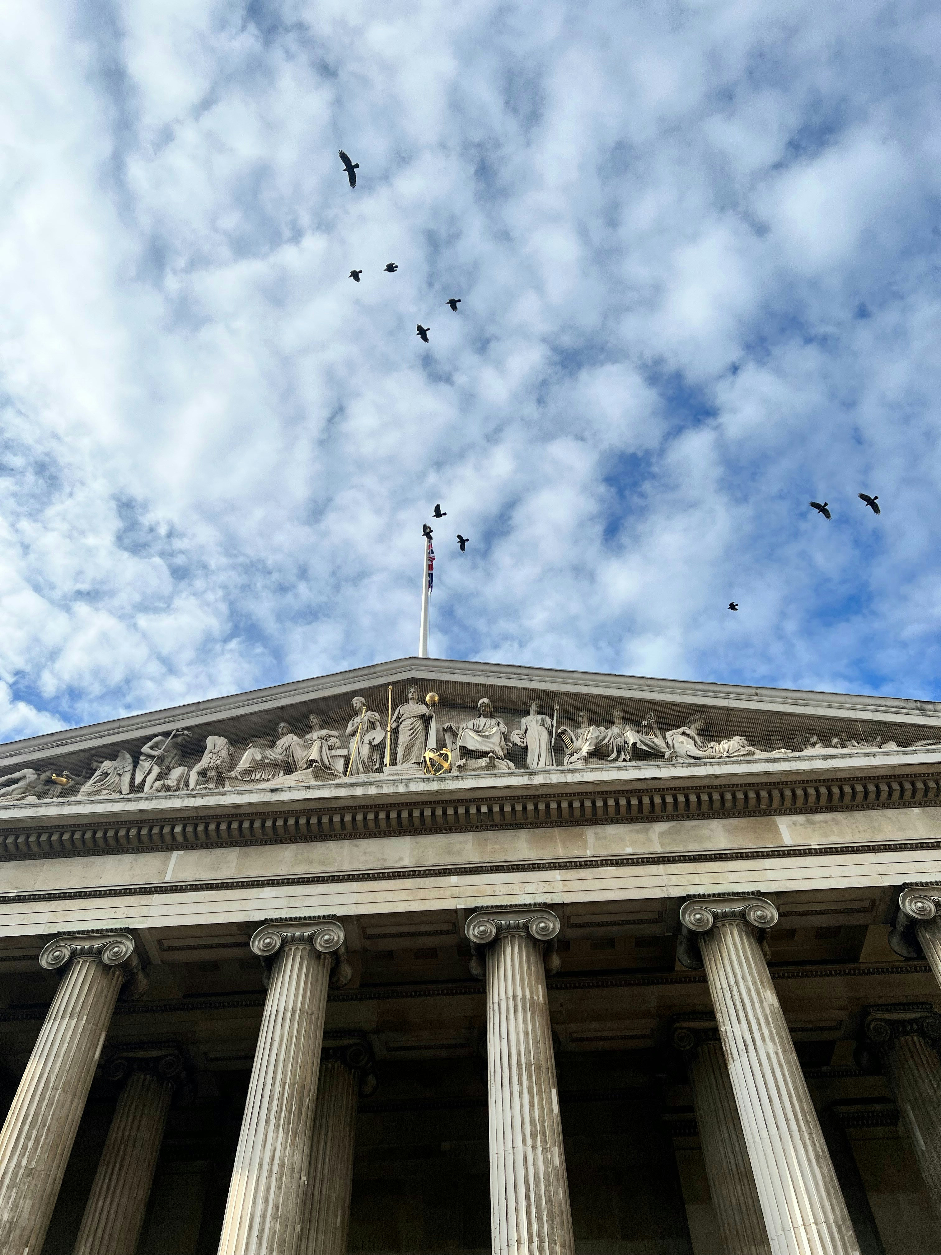 A building with columns and birds flying in the sky photo – Free London ...