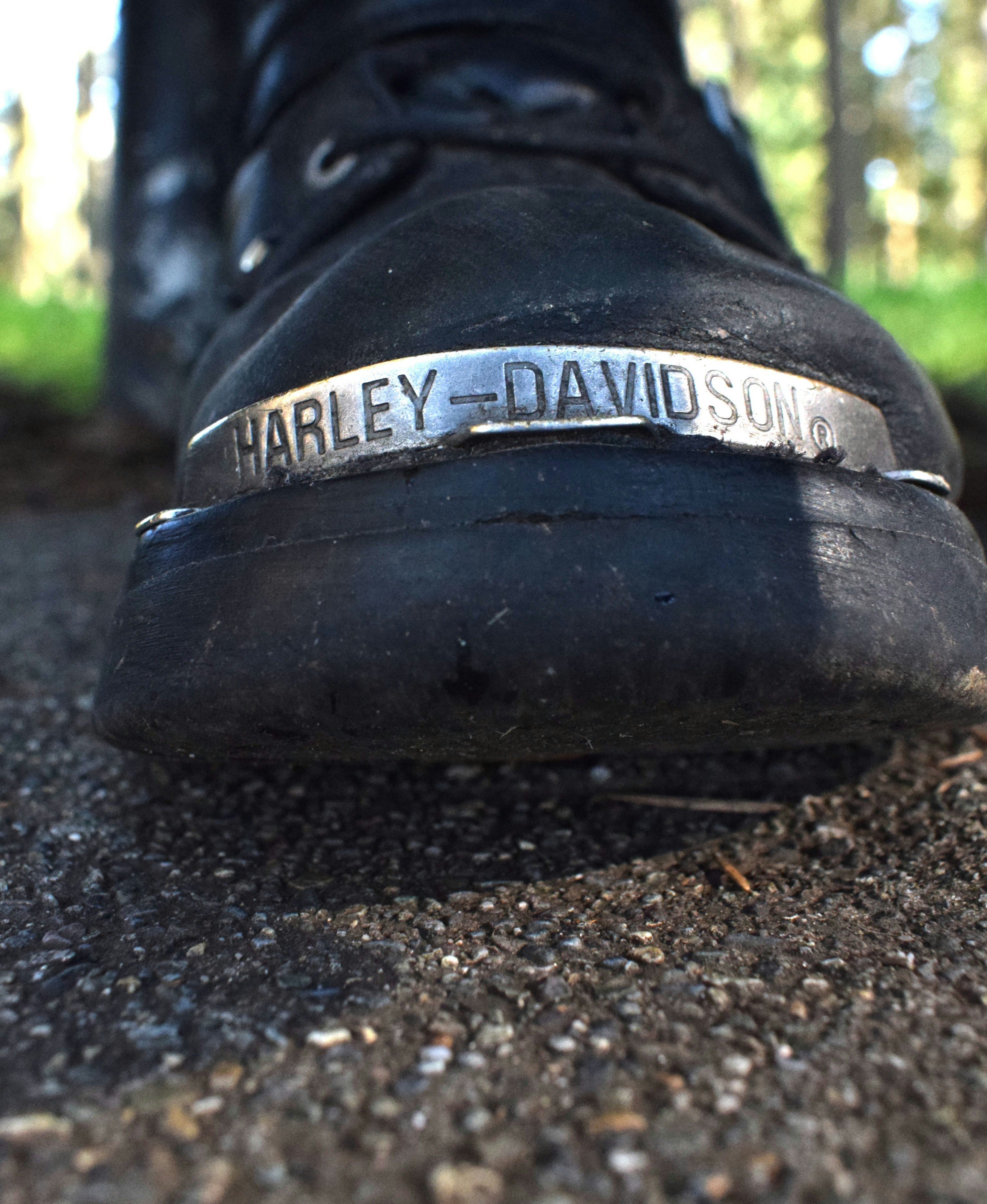 Close-up of a rugged boot with Harley‑Davidson emblem at ground level