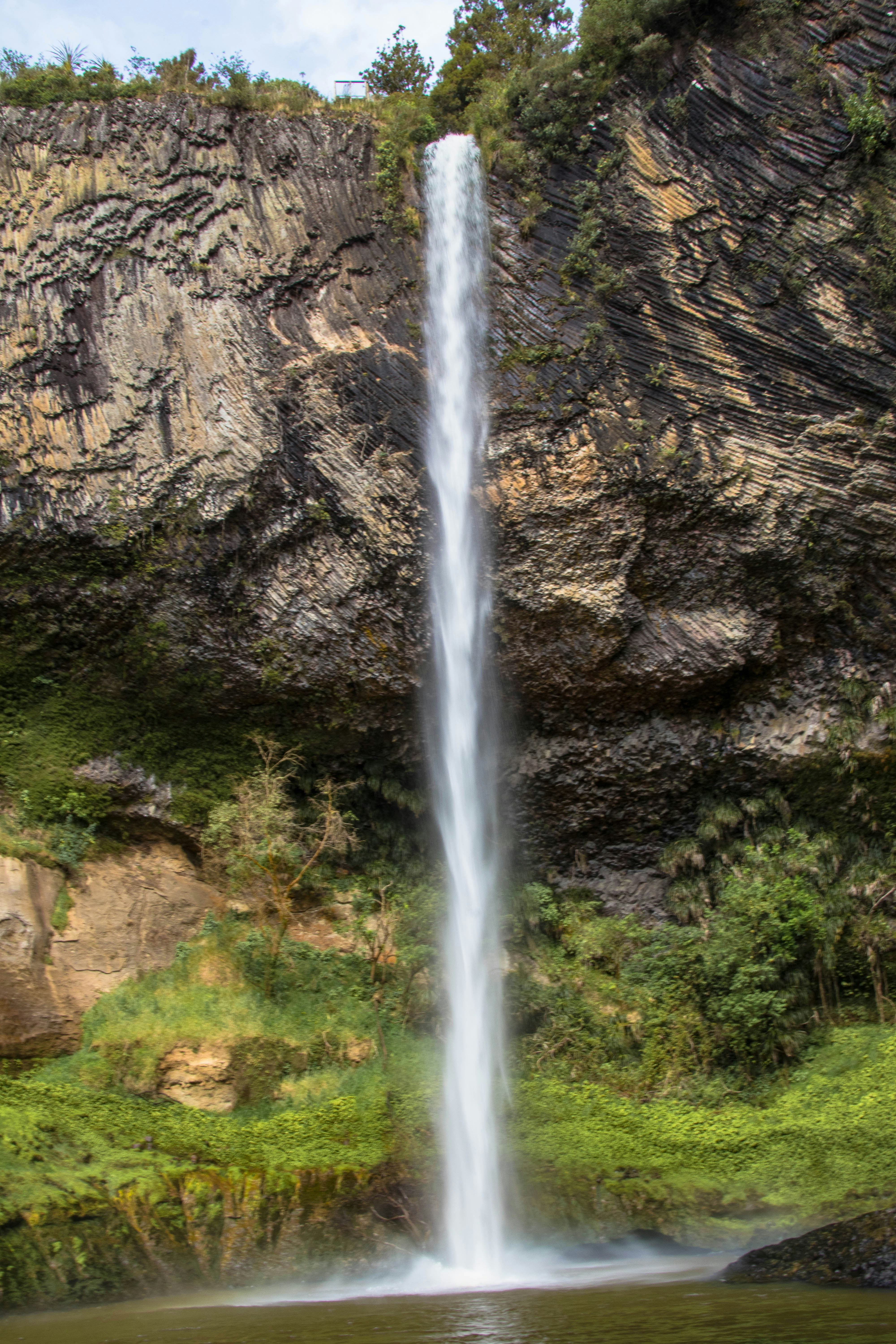 A very tall waterfall in the middle of a body of water photo – Free New ...