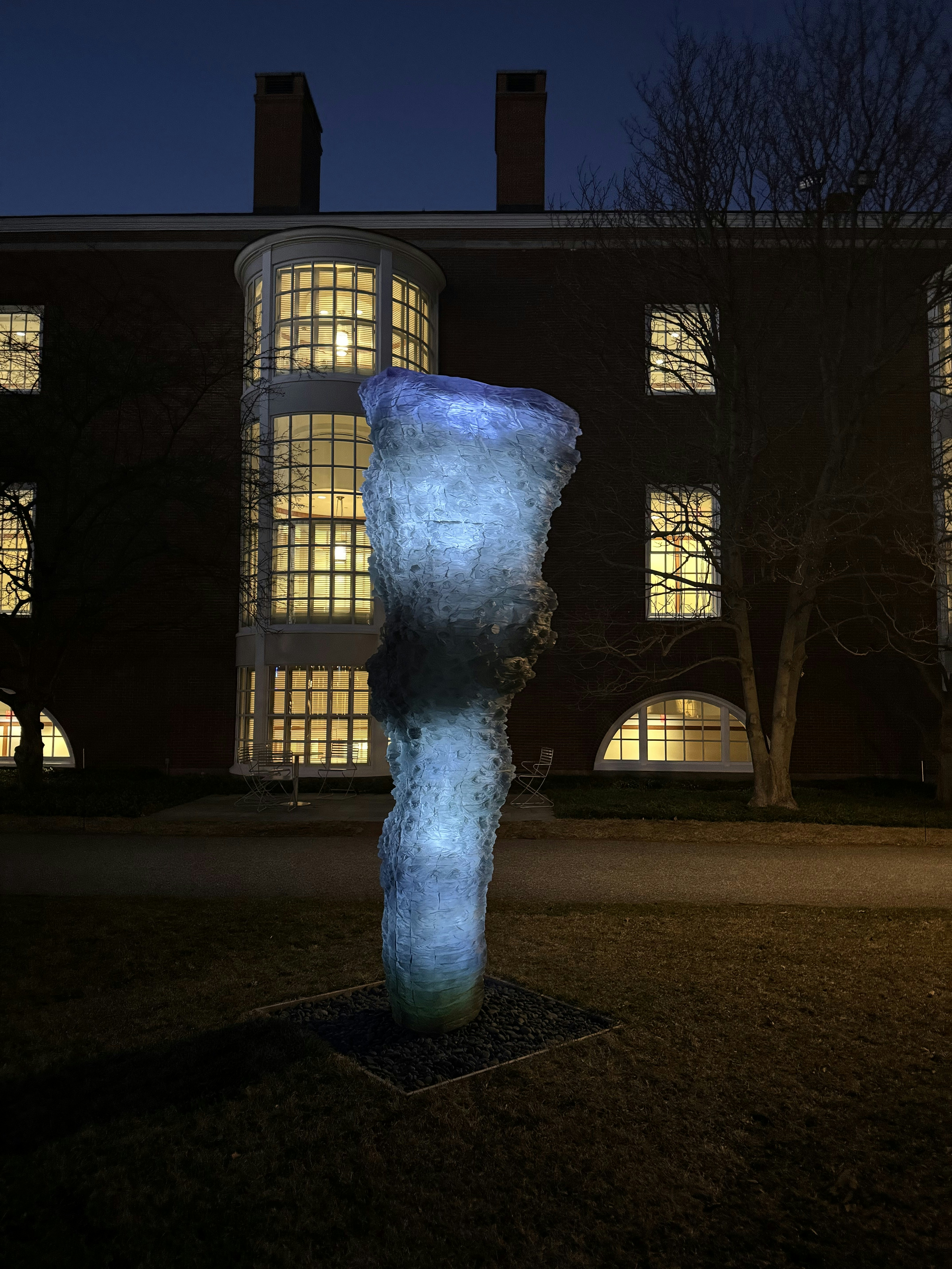 Ice Column Under Moonlit Night: A Glowing Sculpture in Front of a Brick Building