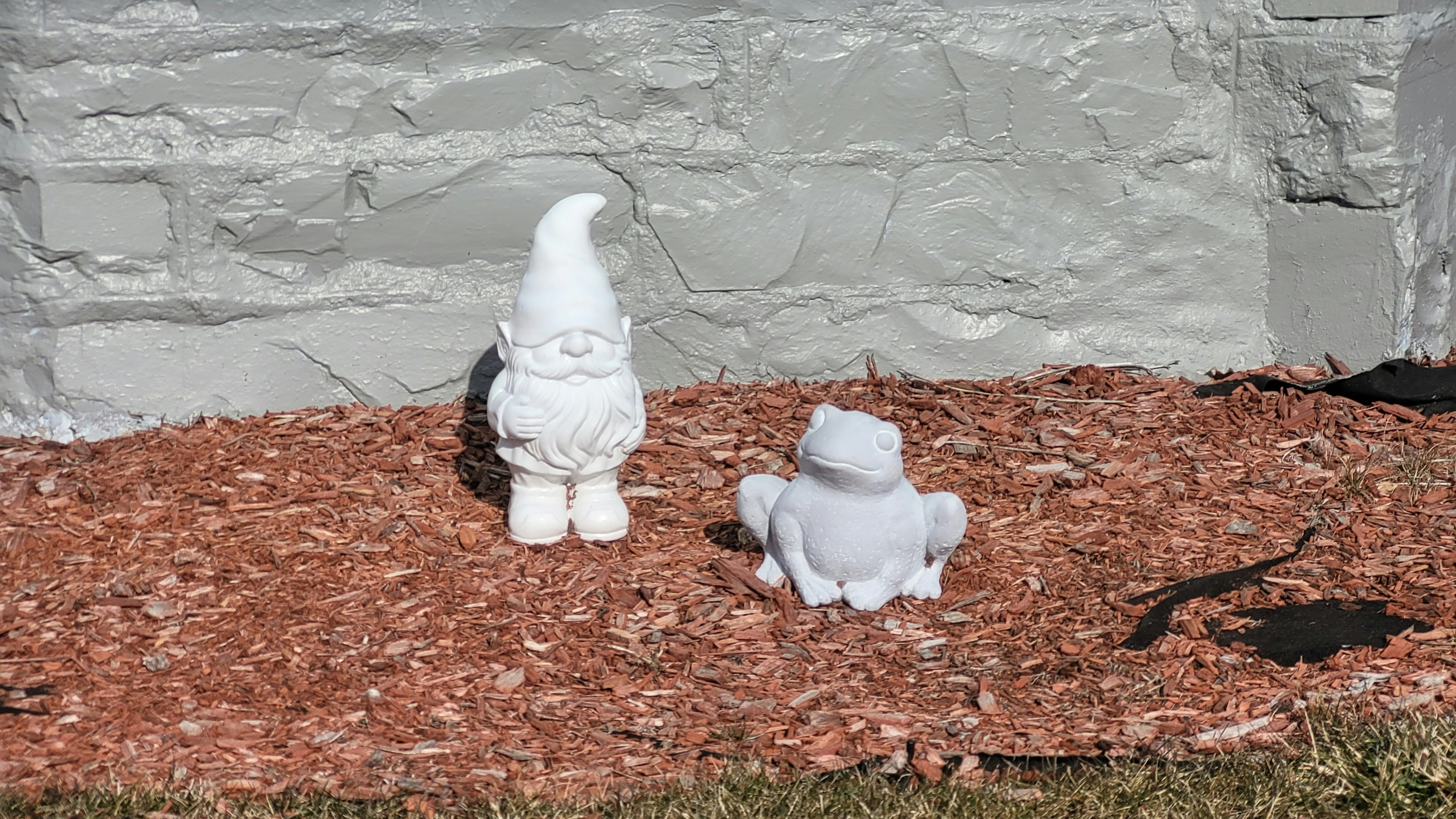 Snowy Garden Quiet: A Pair of White Figurines Among Mulch