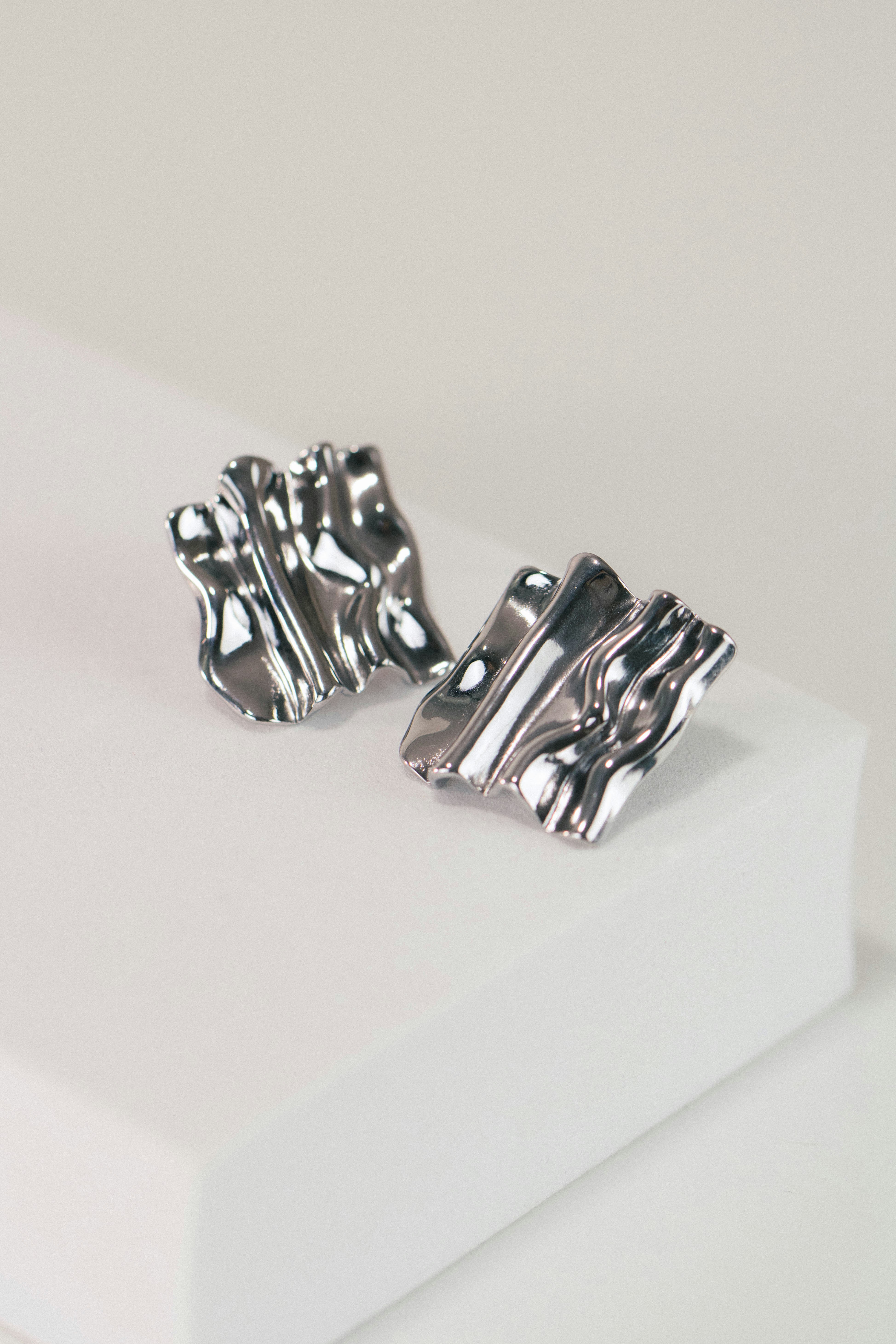 Chromed Friction: Abstract Jewelry on a White Pedestal
