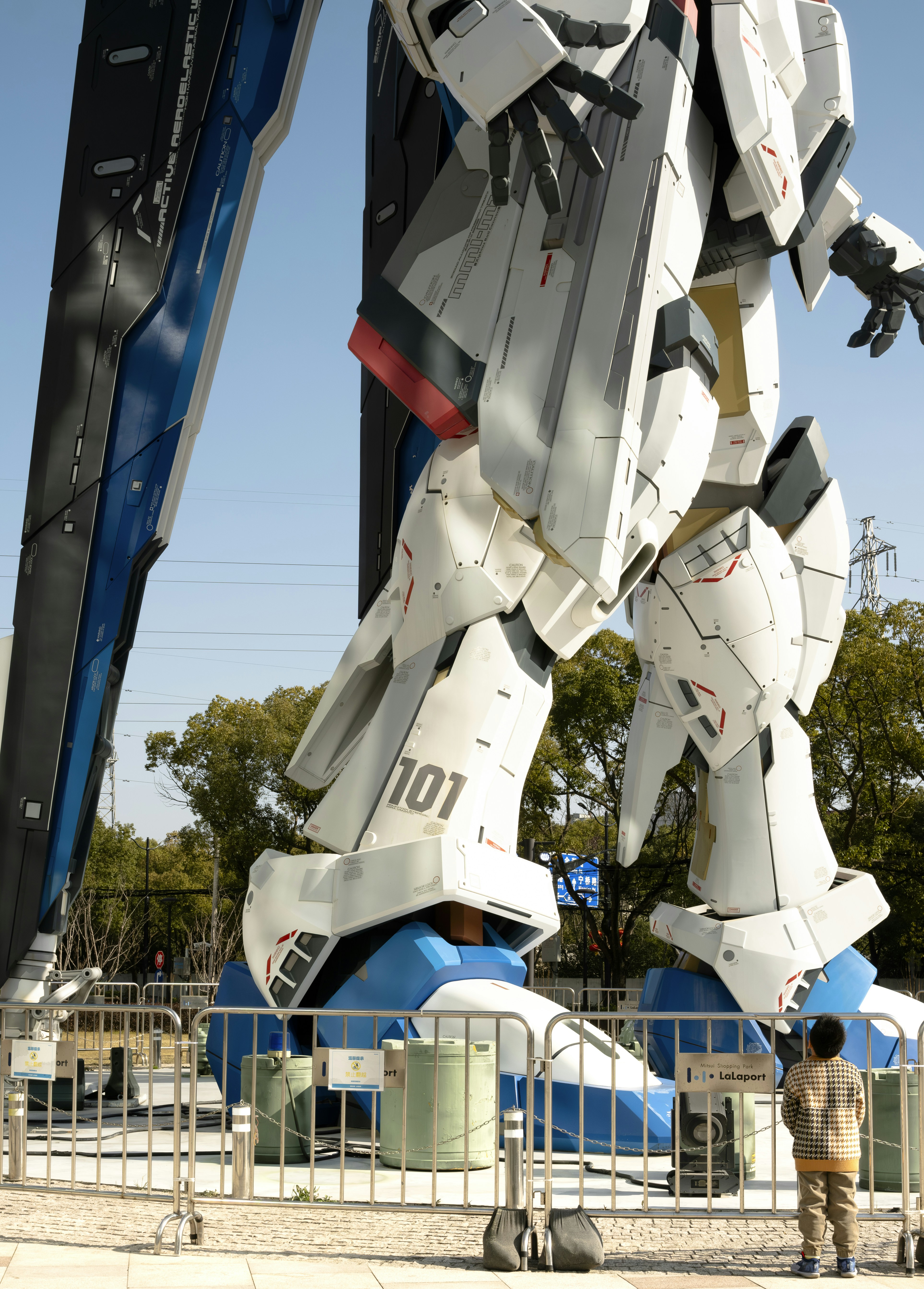 Rising Giant: A White Gundam-Style Statue in a Sunlit Plaza